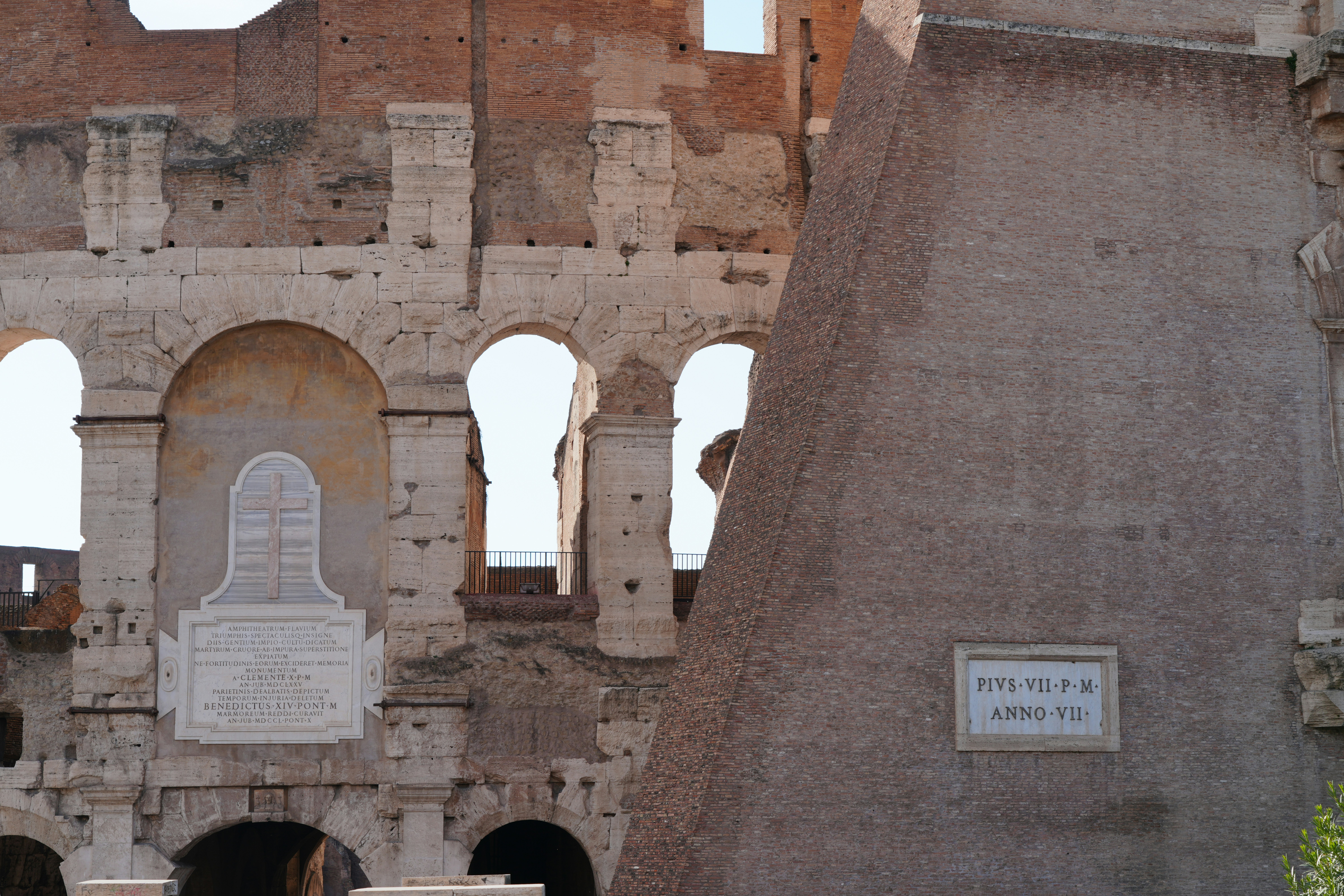 Crumbled Roman amphitheater walls frame a weathered plaque and stone monument