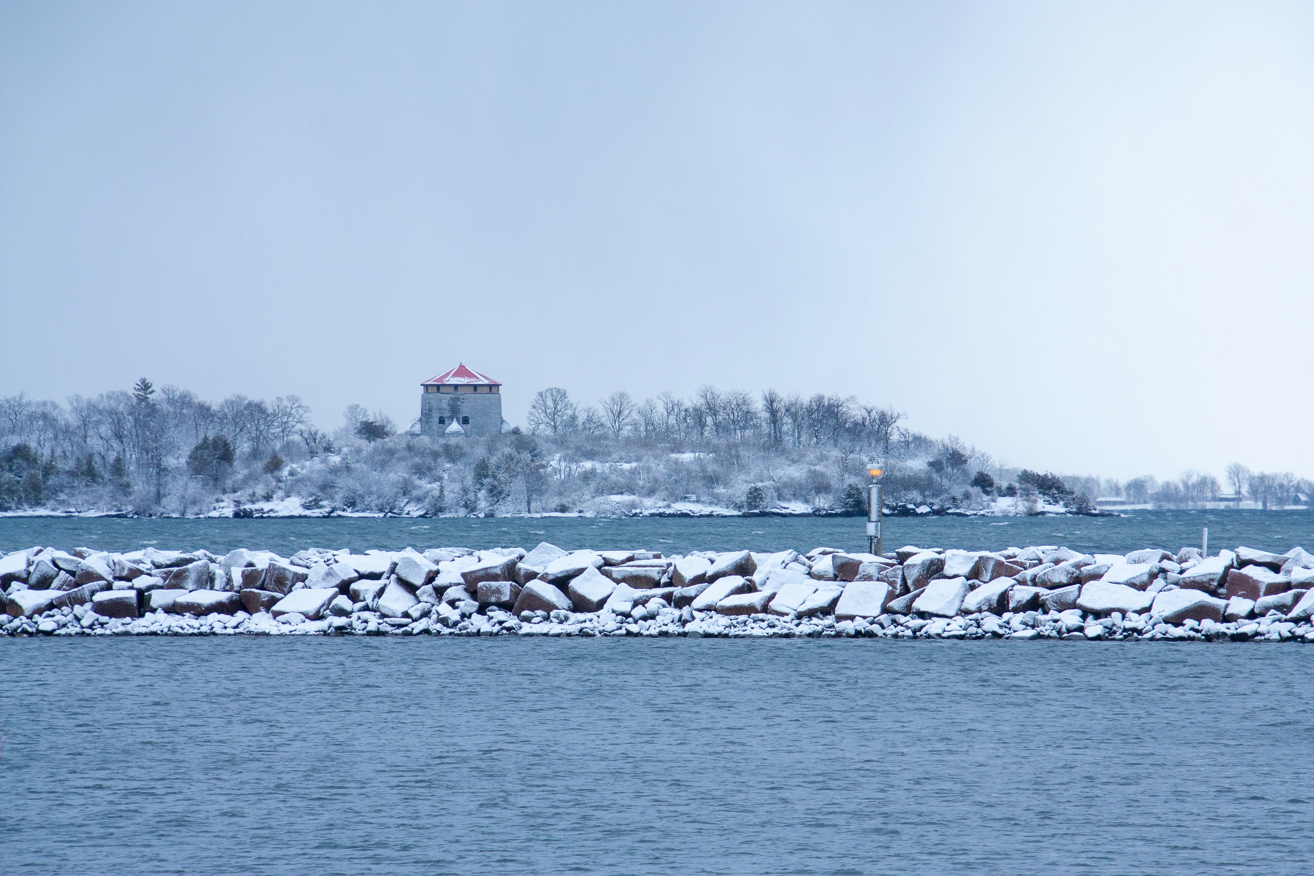 Snowbound Beacon: A Far shore with a lone red-roofed tower