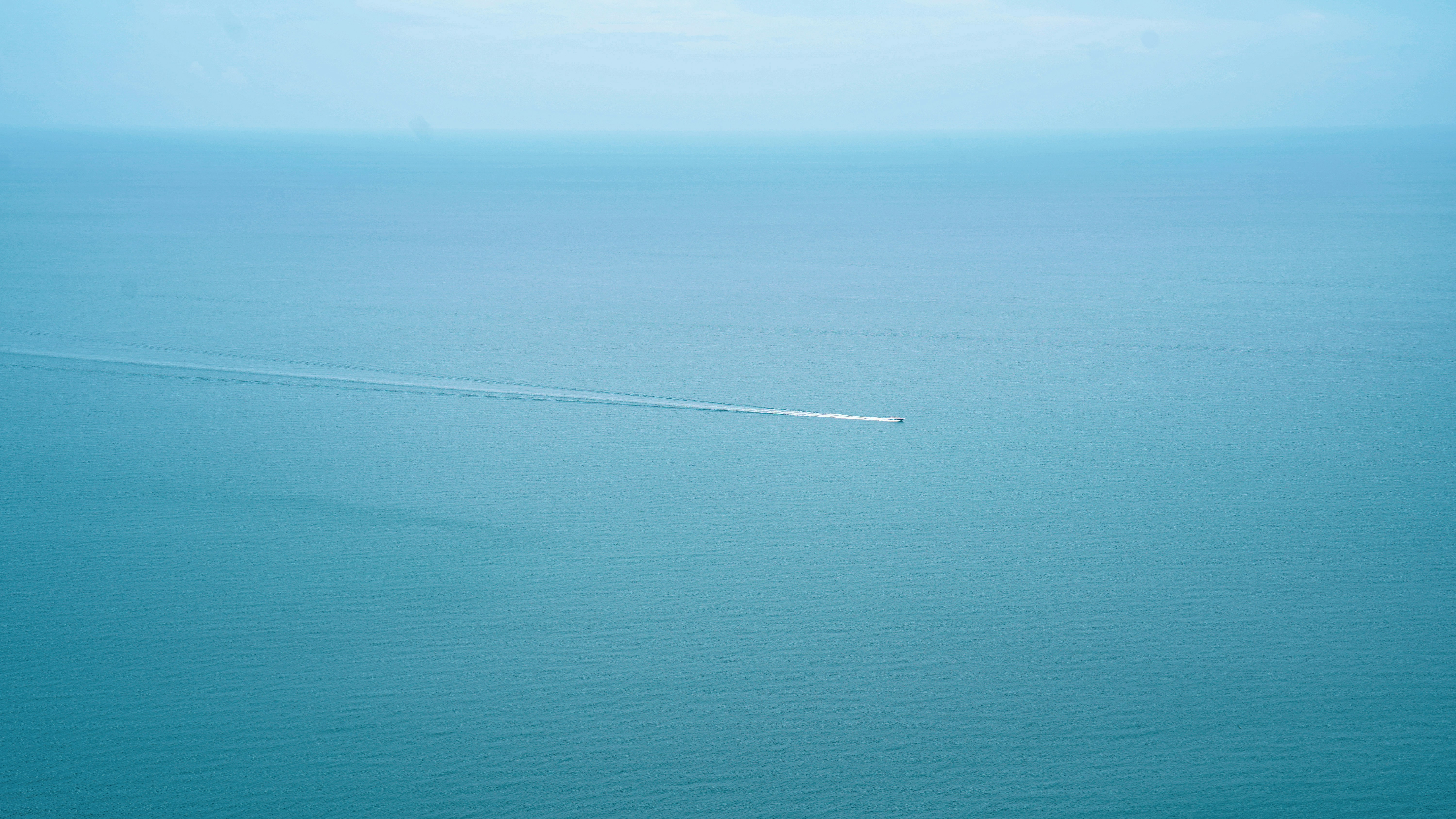 A Quiet Sliver of Wake: Vessel Tracing a Narrow Line Across Infinite Blue