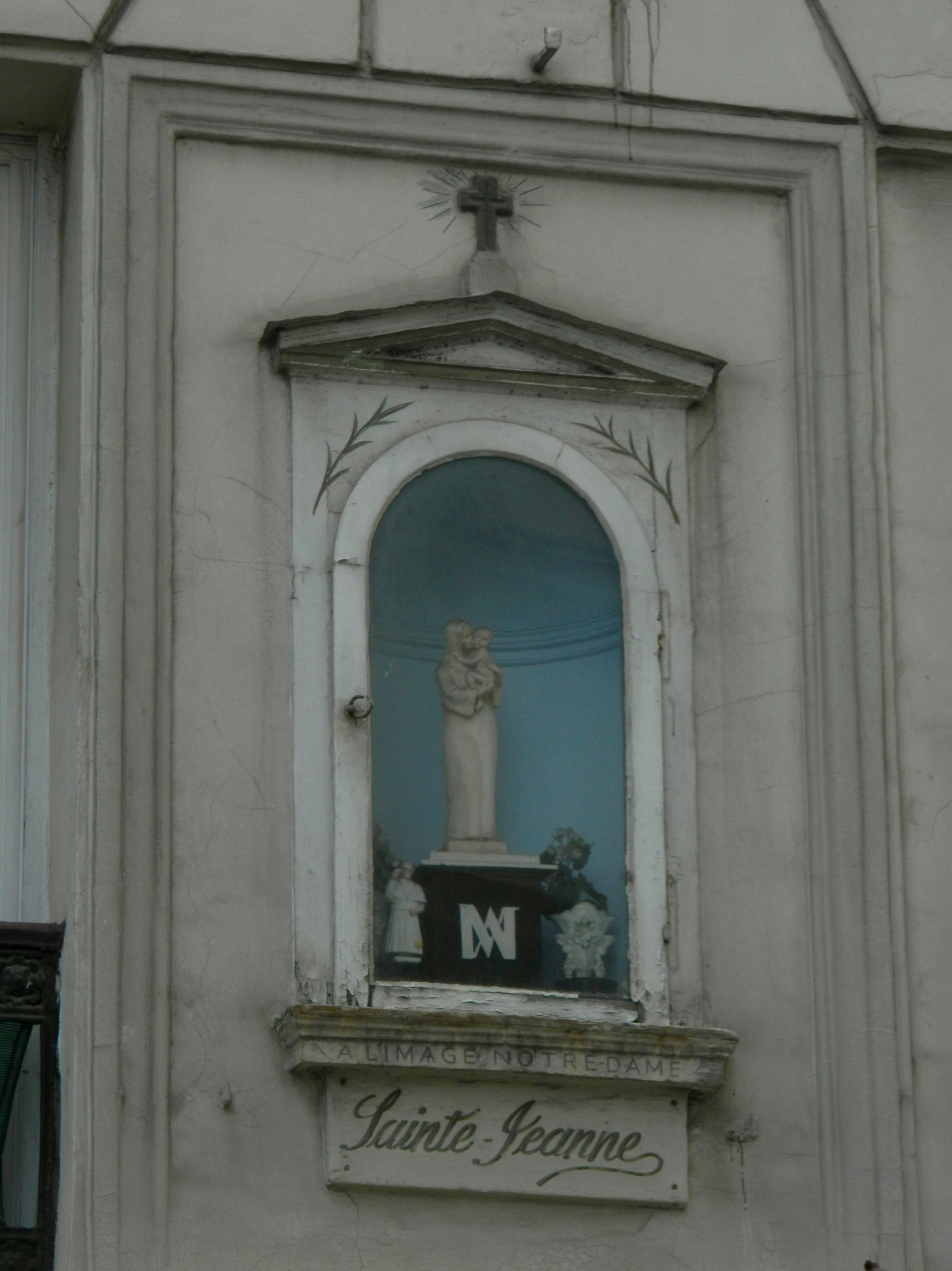 Niche Shrine: A Weathered Figurine Framed in a Timeworn Arch