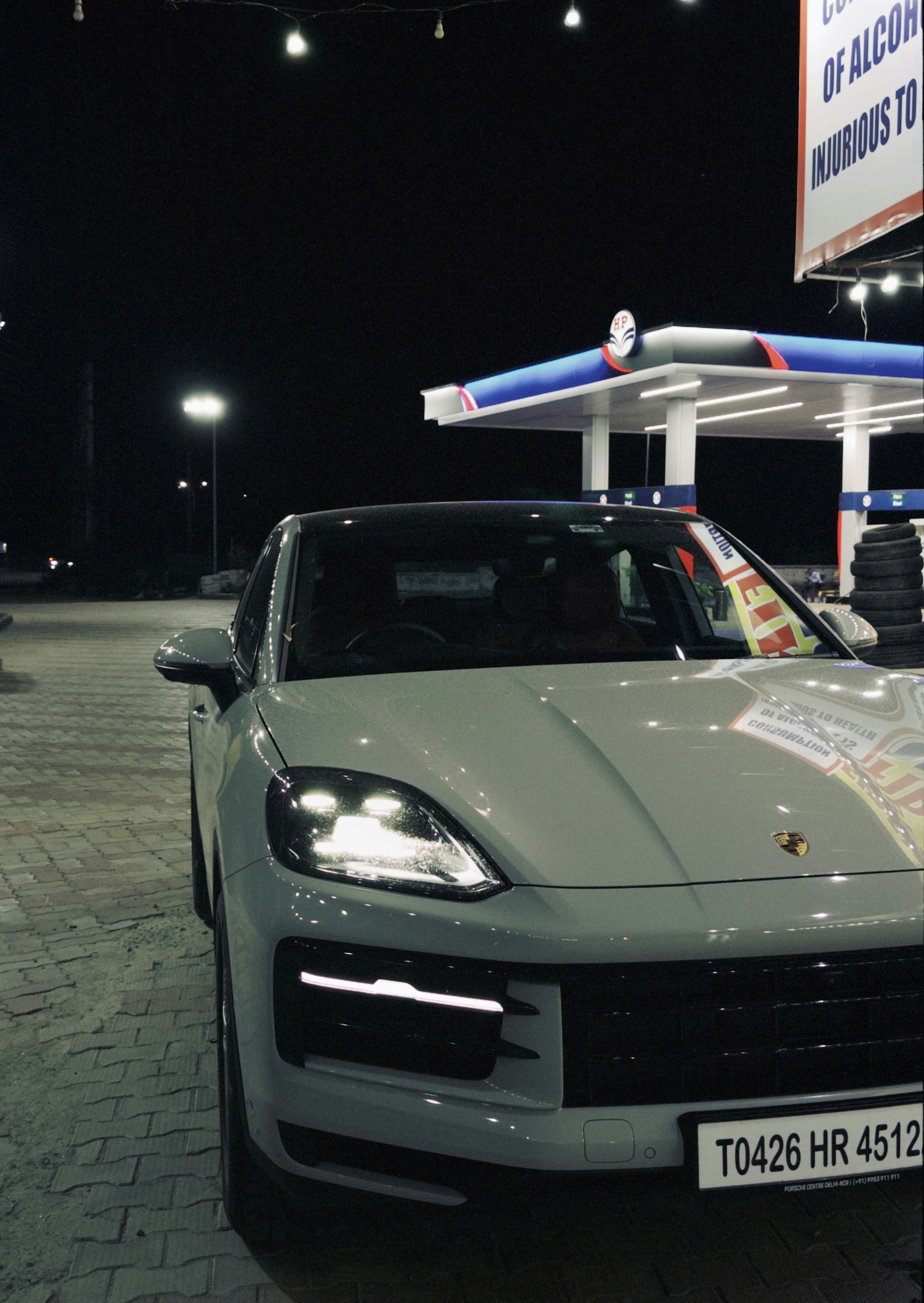 White Porsche at a dimly lit fuel stop under night skies