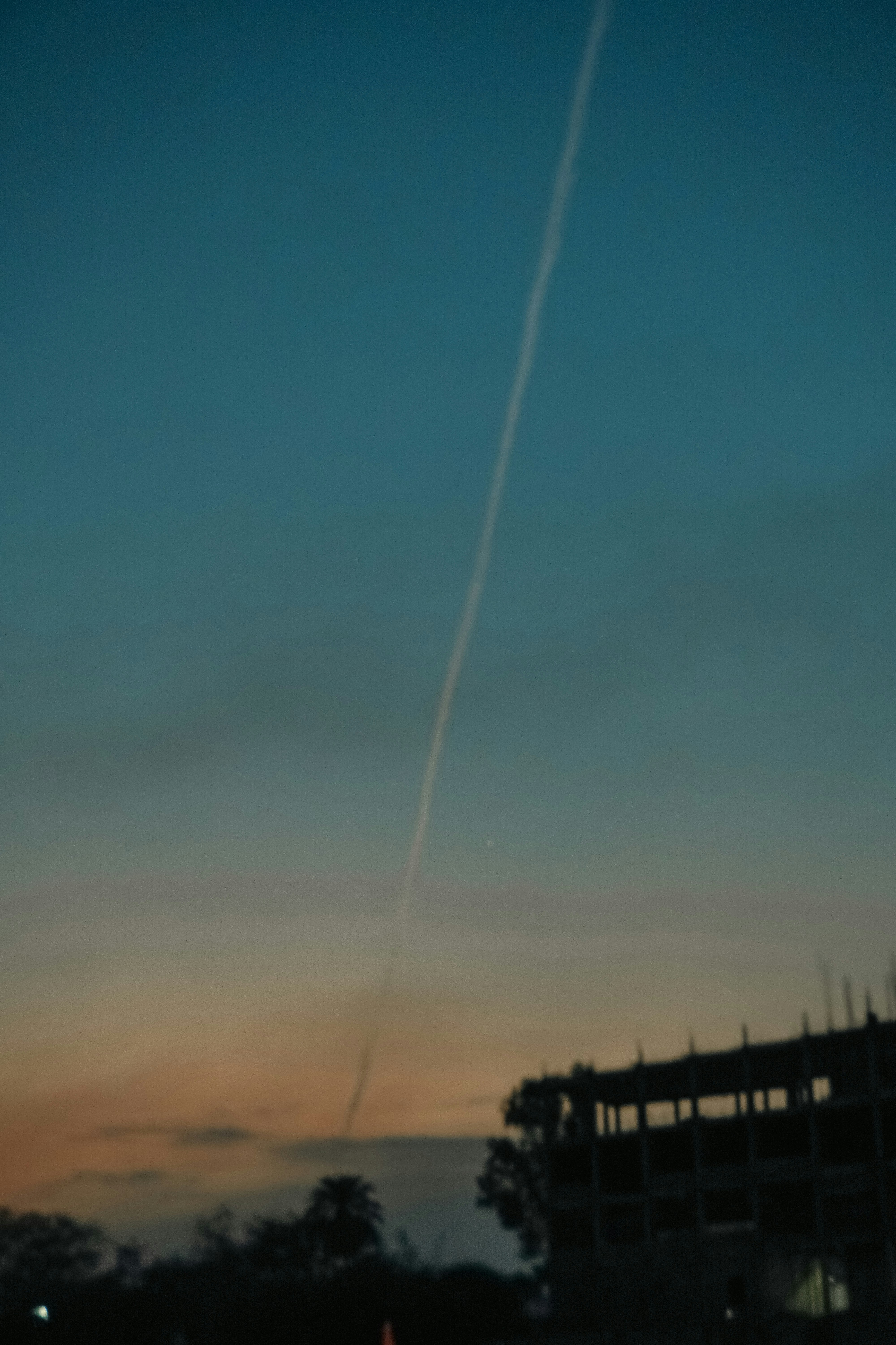 Skyline Silhouette Under a Diagonal Contrail