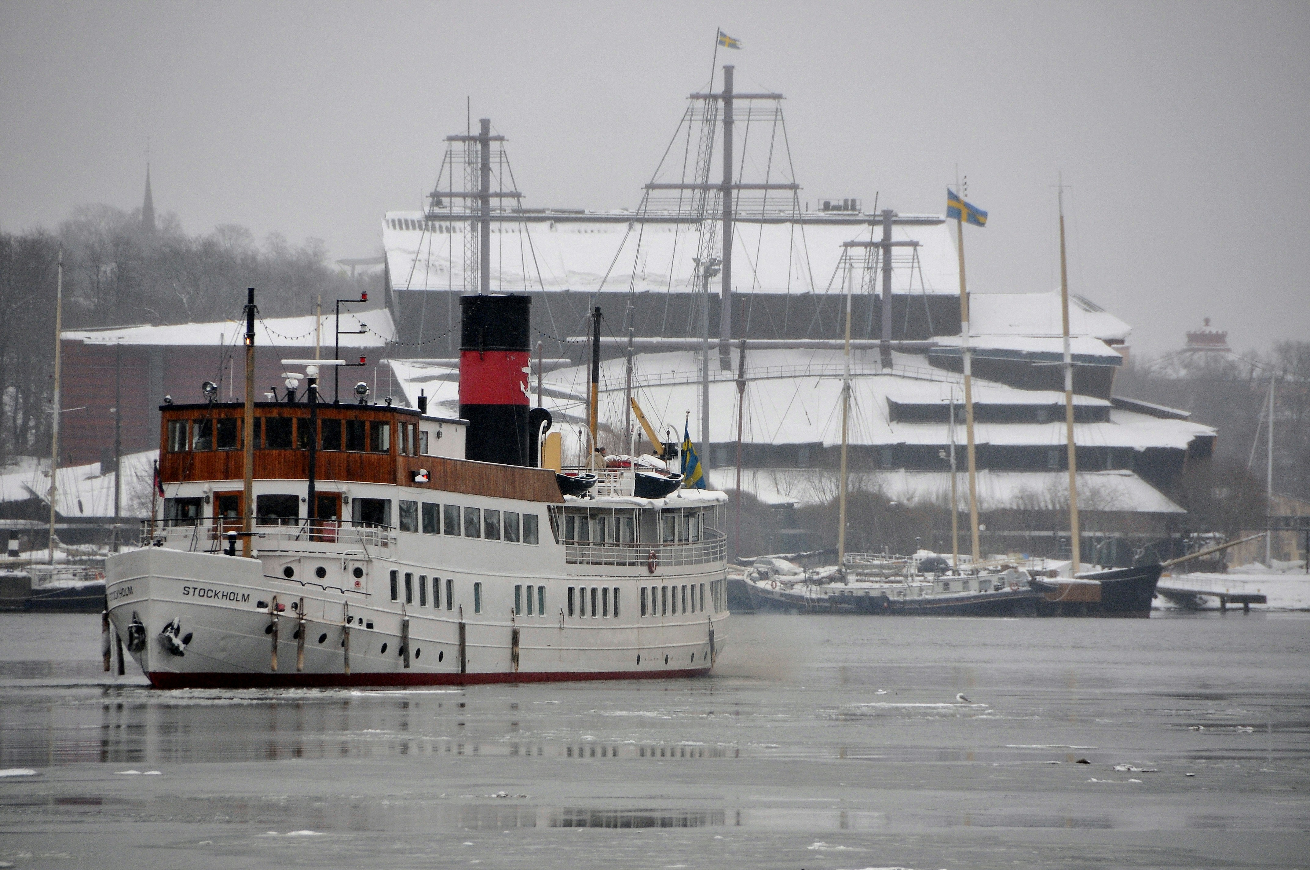 Historic steamship gliding past a modern harbor snow-scape