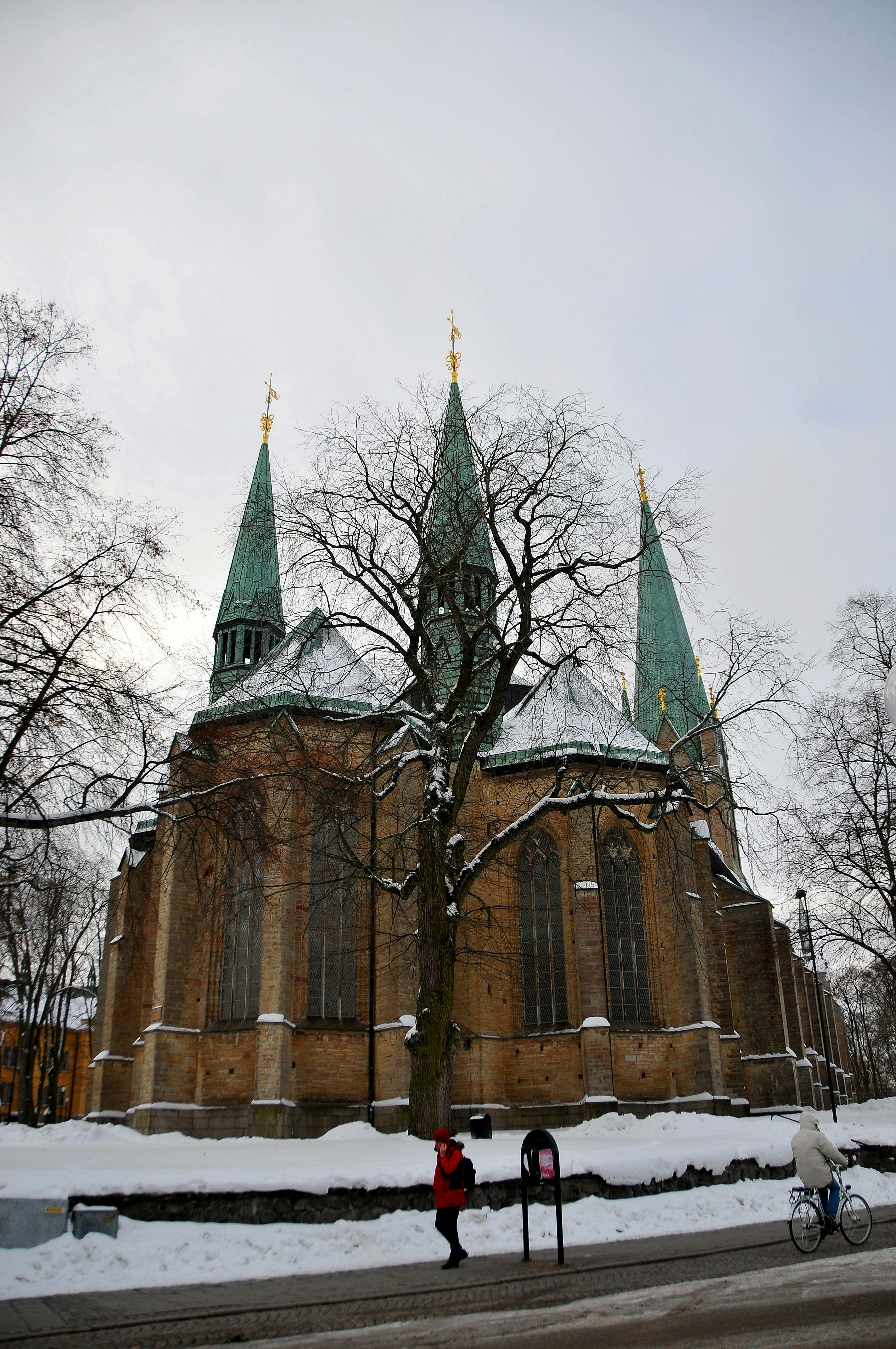 Cathedral in Winter: A Red-Booted Figure by the Snow-Wrapped Brick