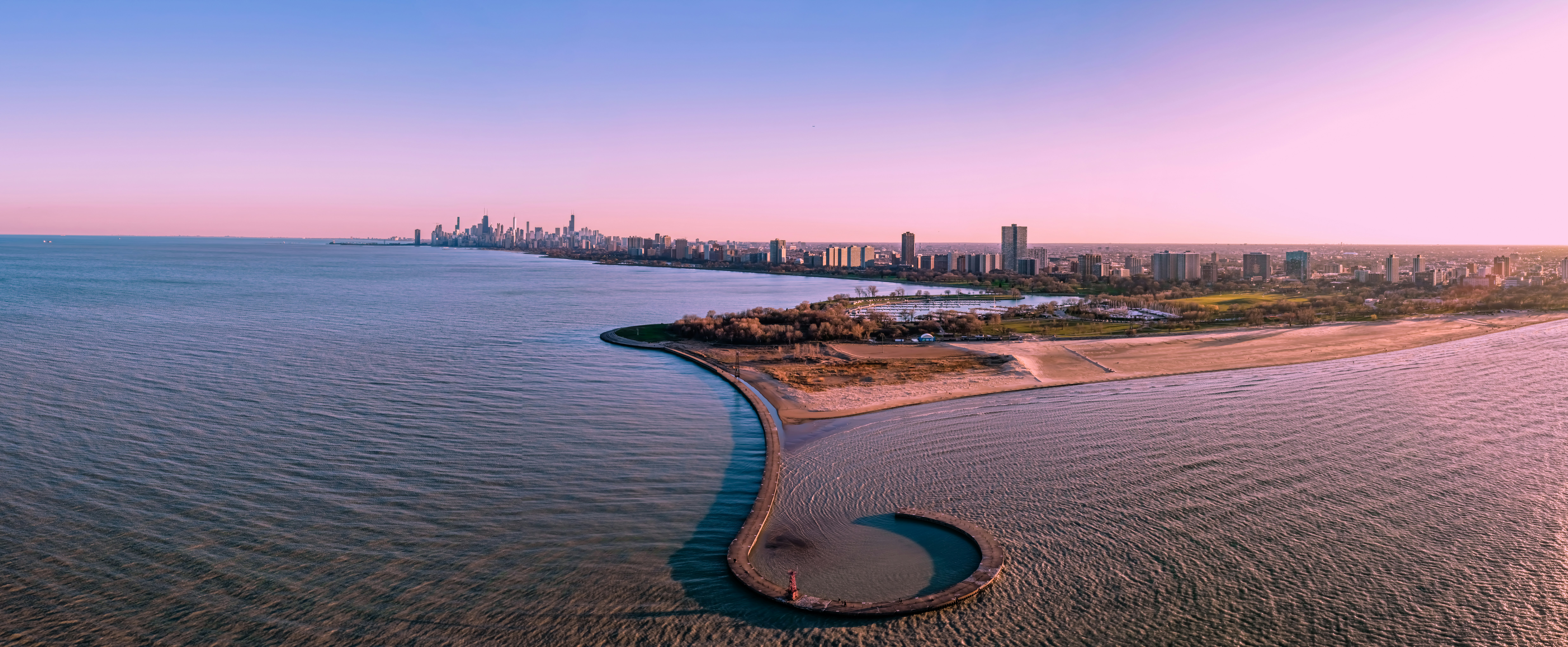 Harbor Curve: Aerial view of a crescent breakwater guarding a serene coastline