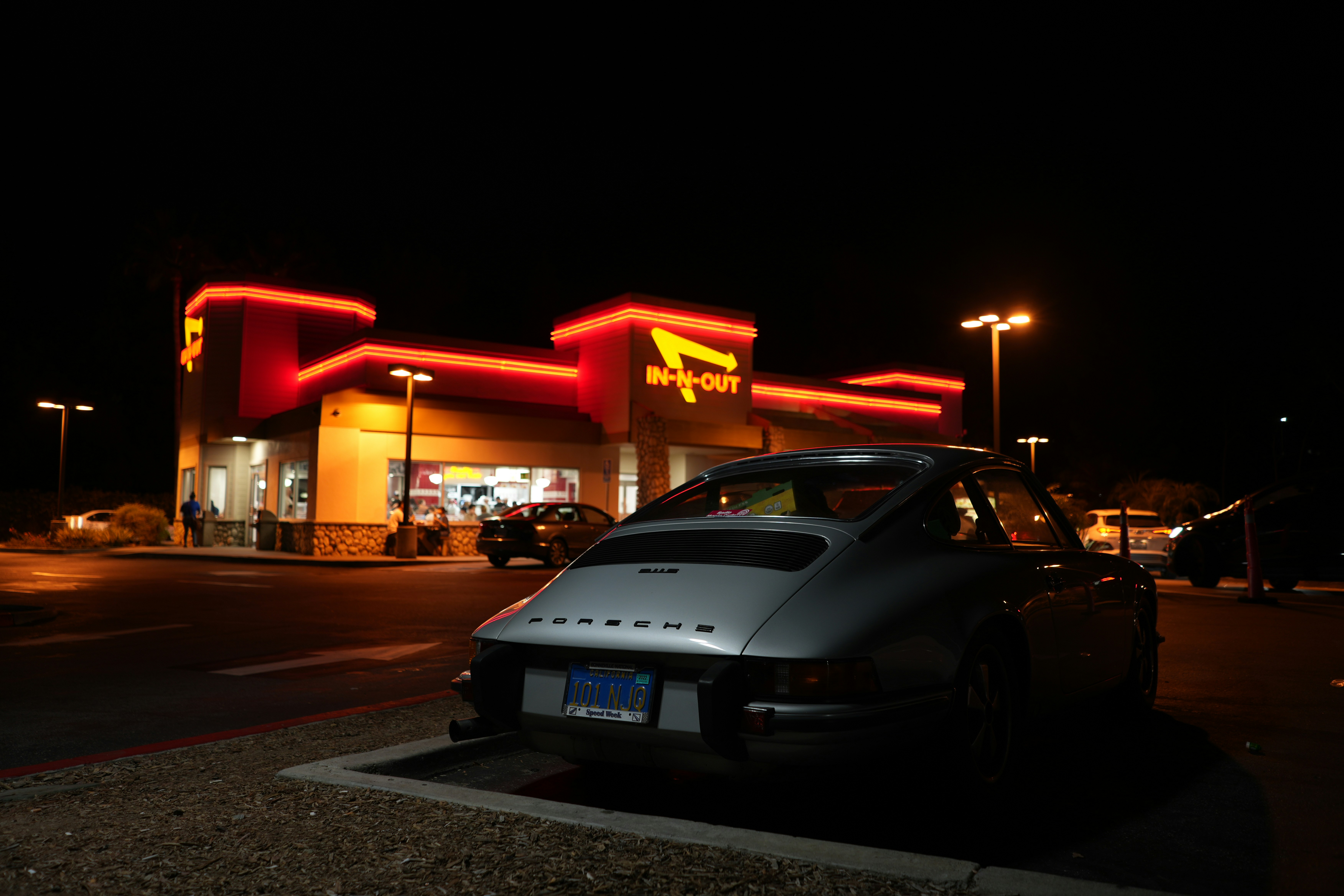 Neon-lit In-N-Out glow over a classic Porsche in the parking lot