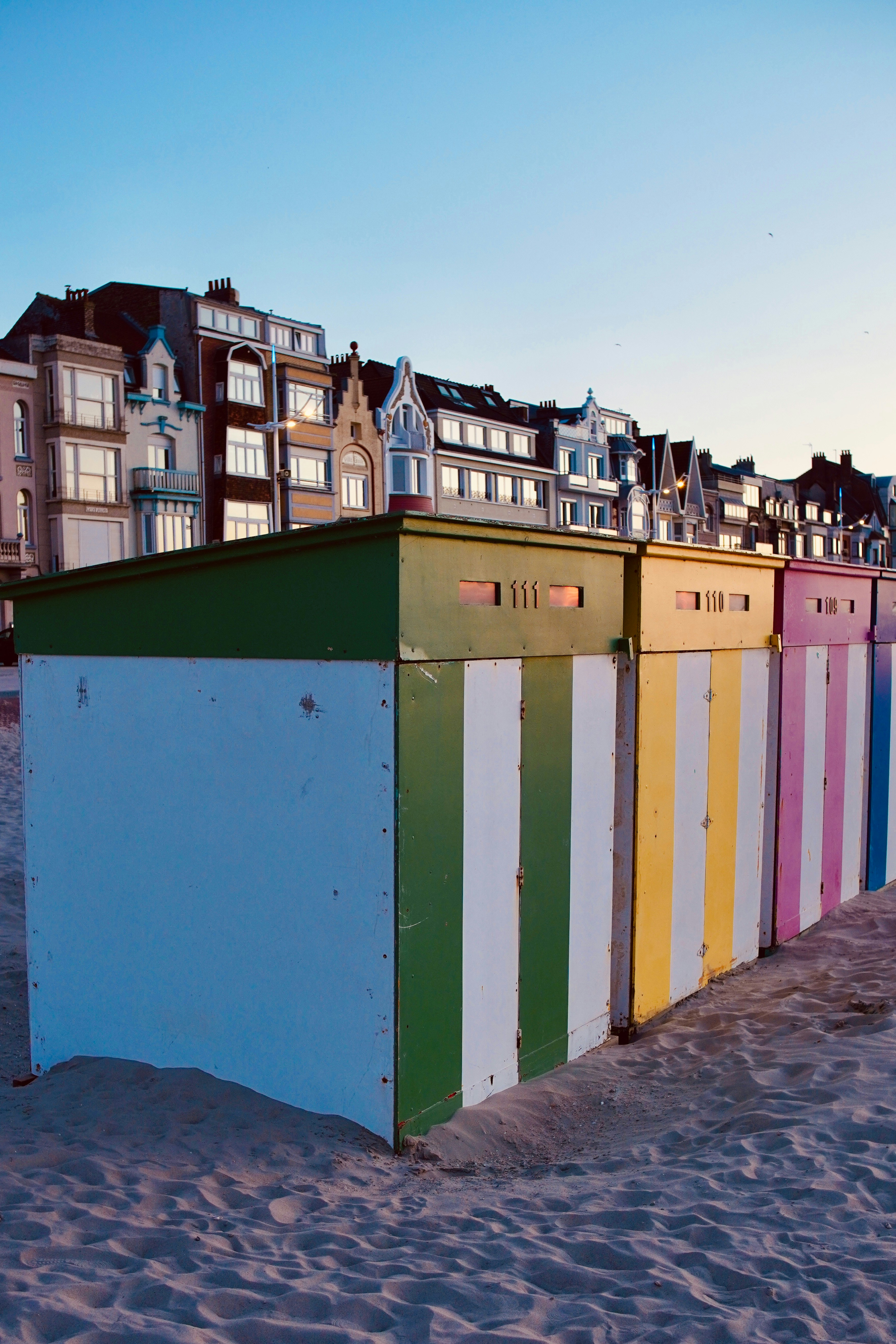 Row of seaside beach huts marching toward pastel skies