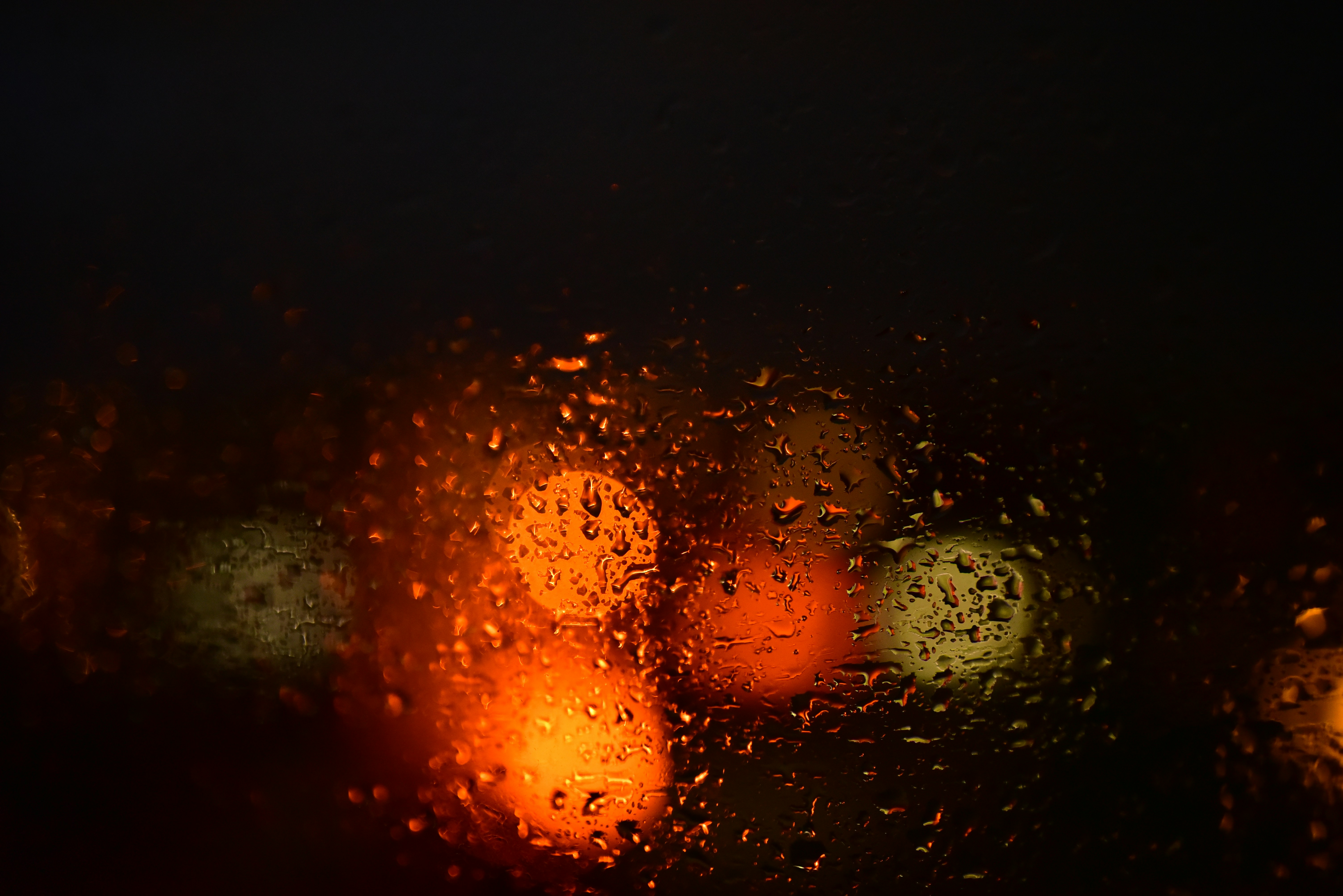 Bokeh Deluge: Warm Orbs Behind Rain-Streaked Glass