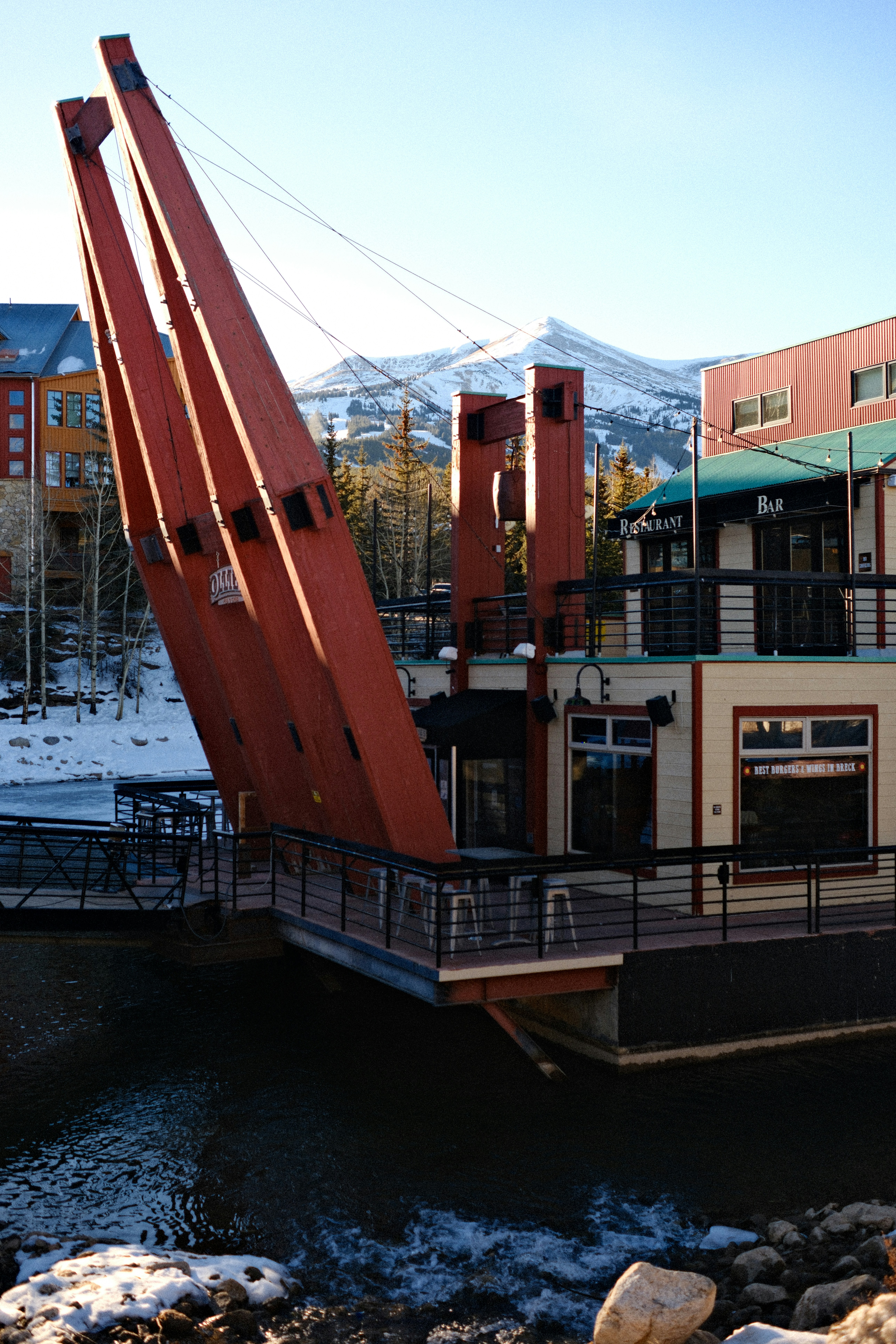 Rusted Anchor on the Dock: A Riverfront Bar and Snow-Capped Peaks
