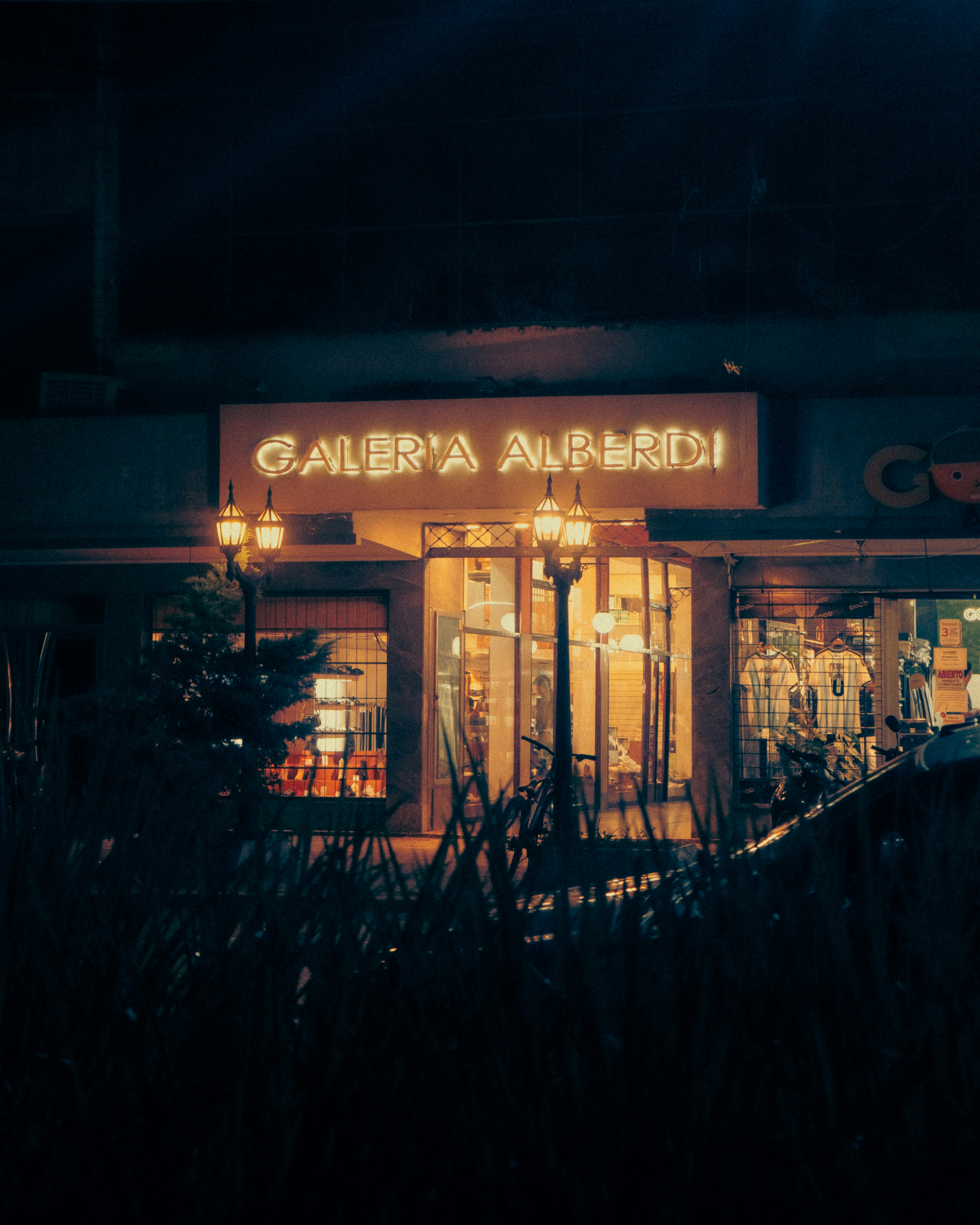 Glow of the Gallery: Night storefront with warm lights in a dim street