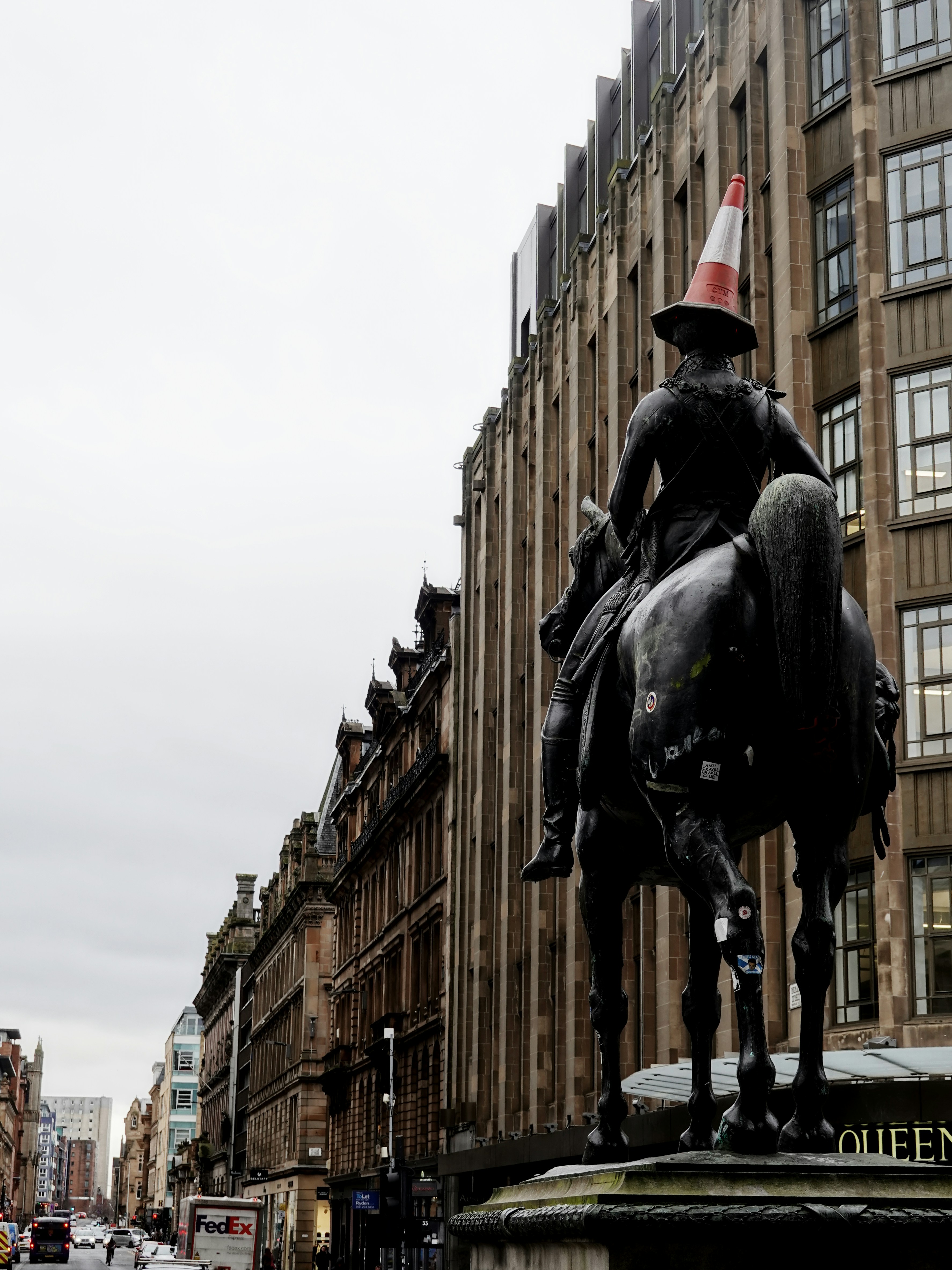 Horse statue under city scaffolding: a lone cone atop the rider