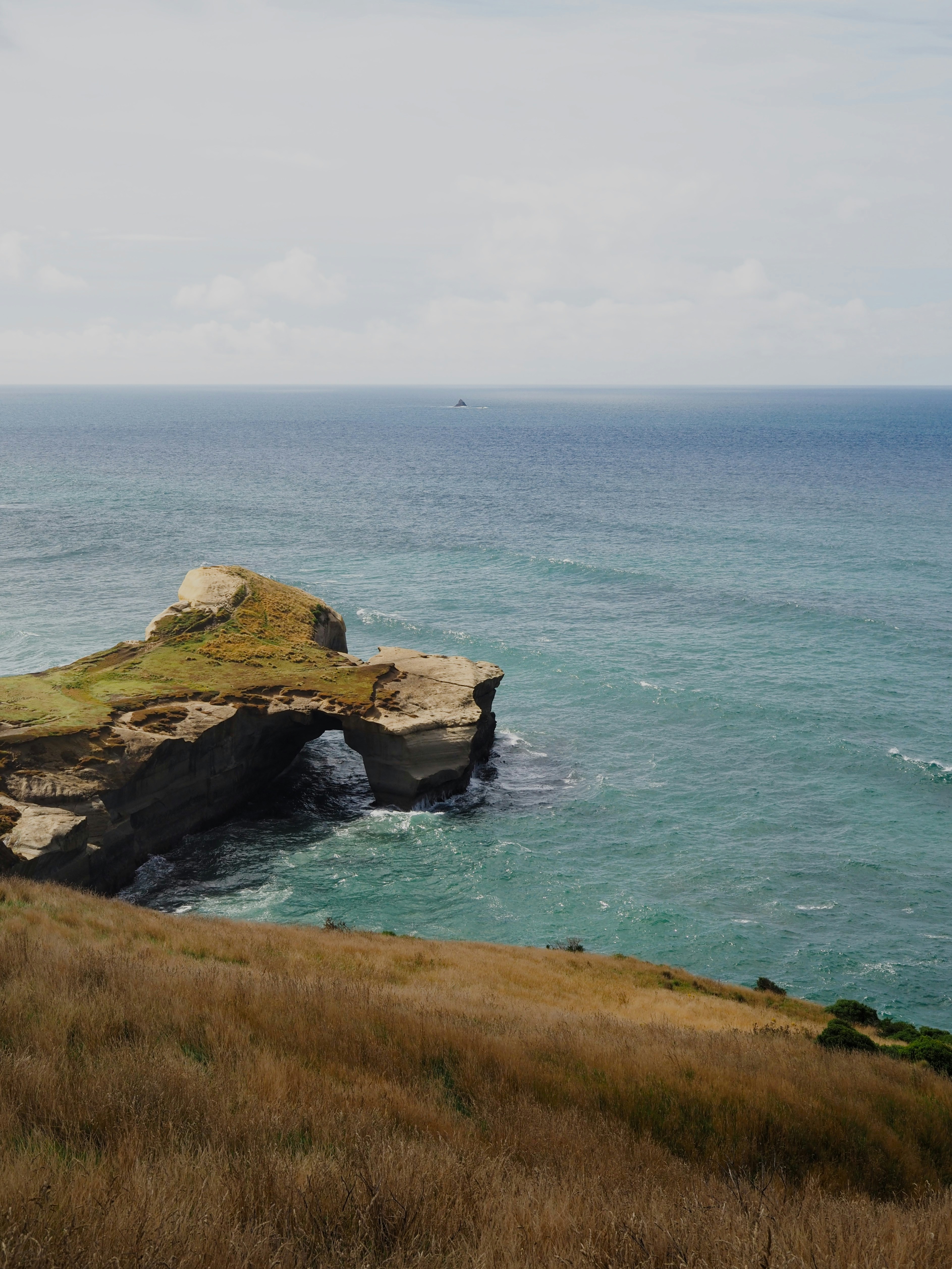 Coastal Arch at Dusk: Sea, Cliff, and Wave-kissed Grass