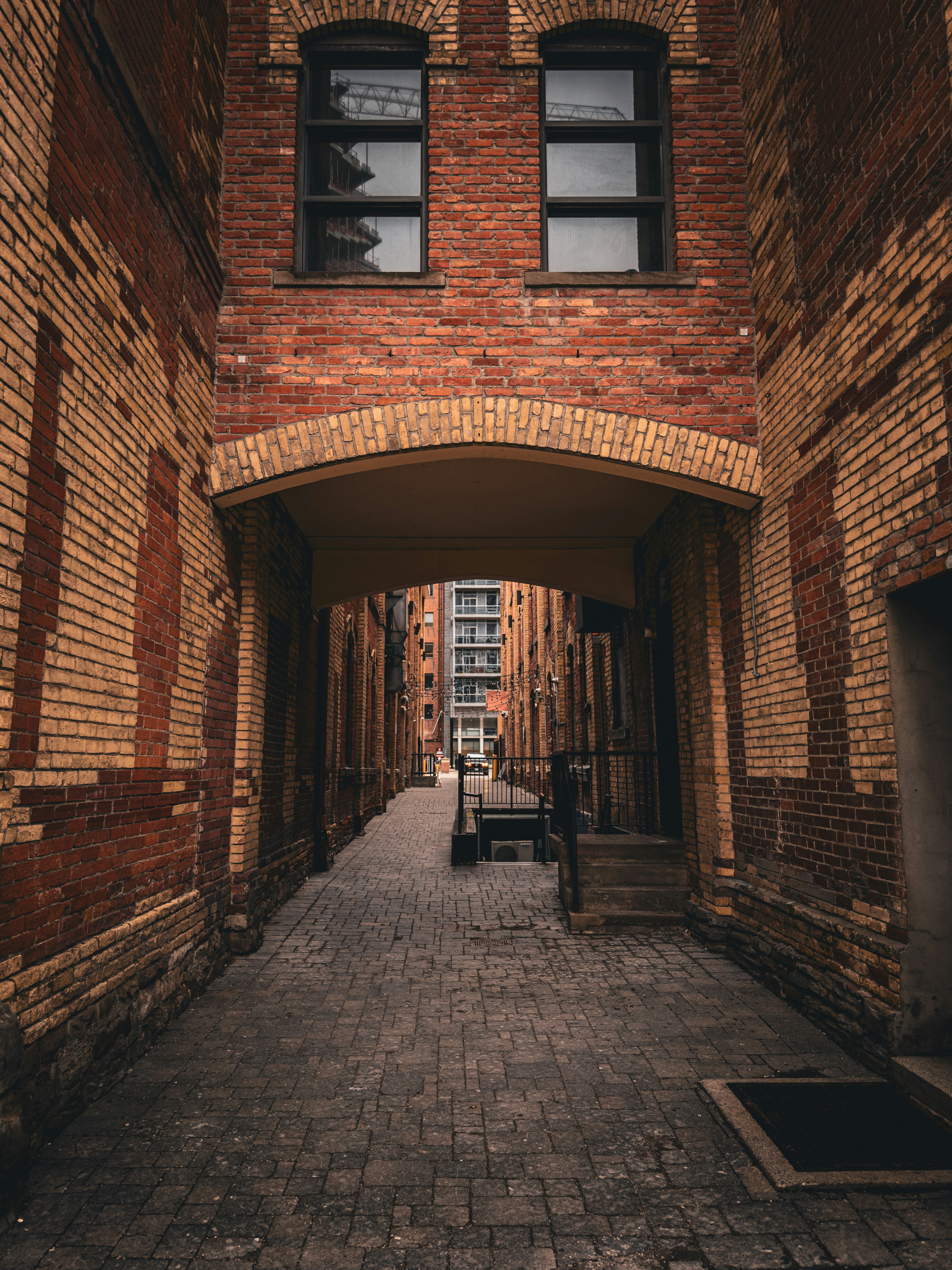 Brick Echoes: A Narrow Alley Framed by Bridges of Sepia Light