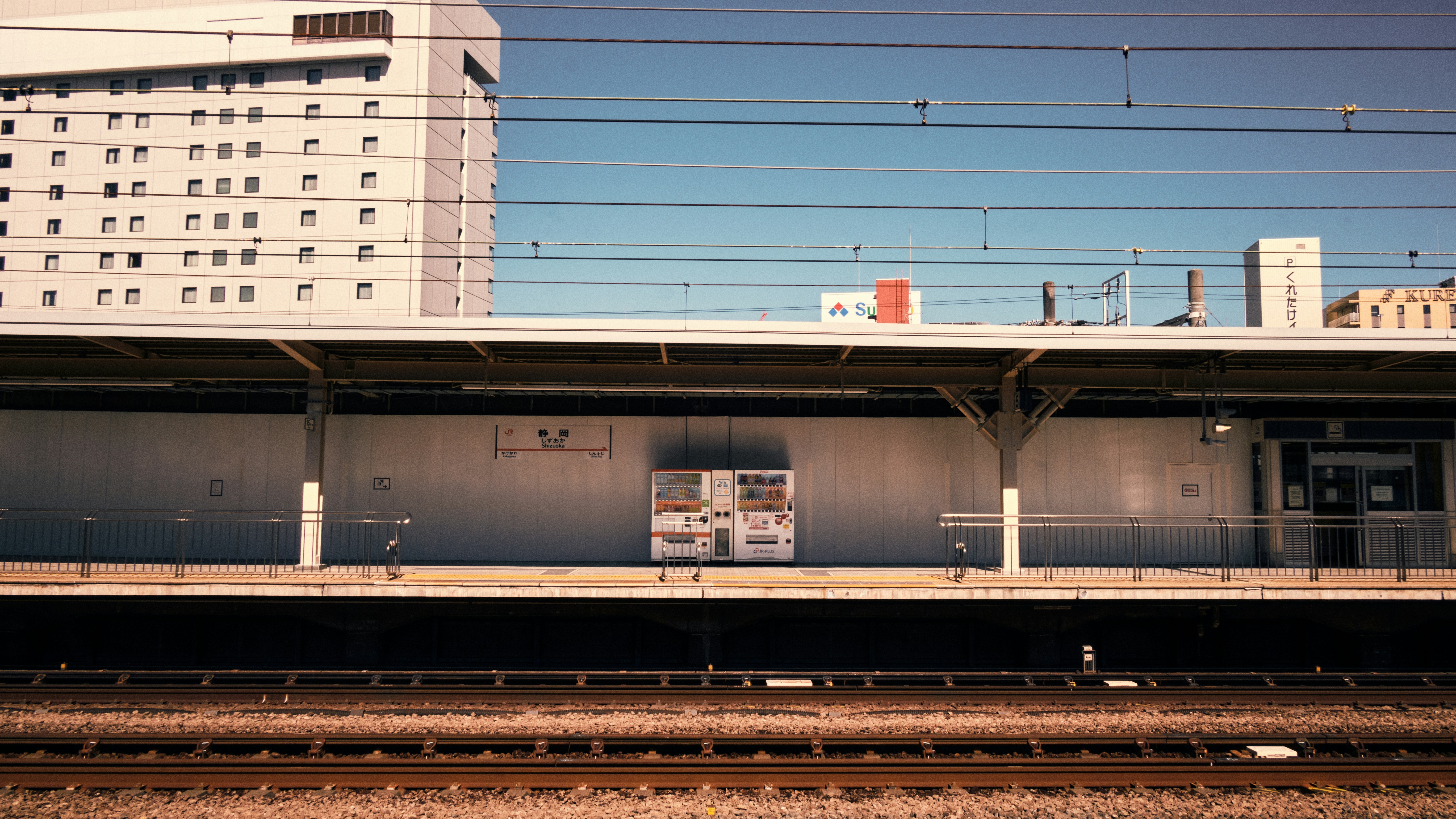 Quiet Platform Overpass: Tracks and Rail Wires under Blue Sky