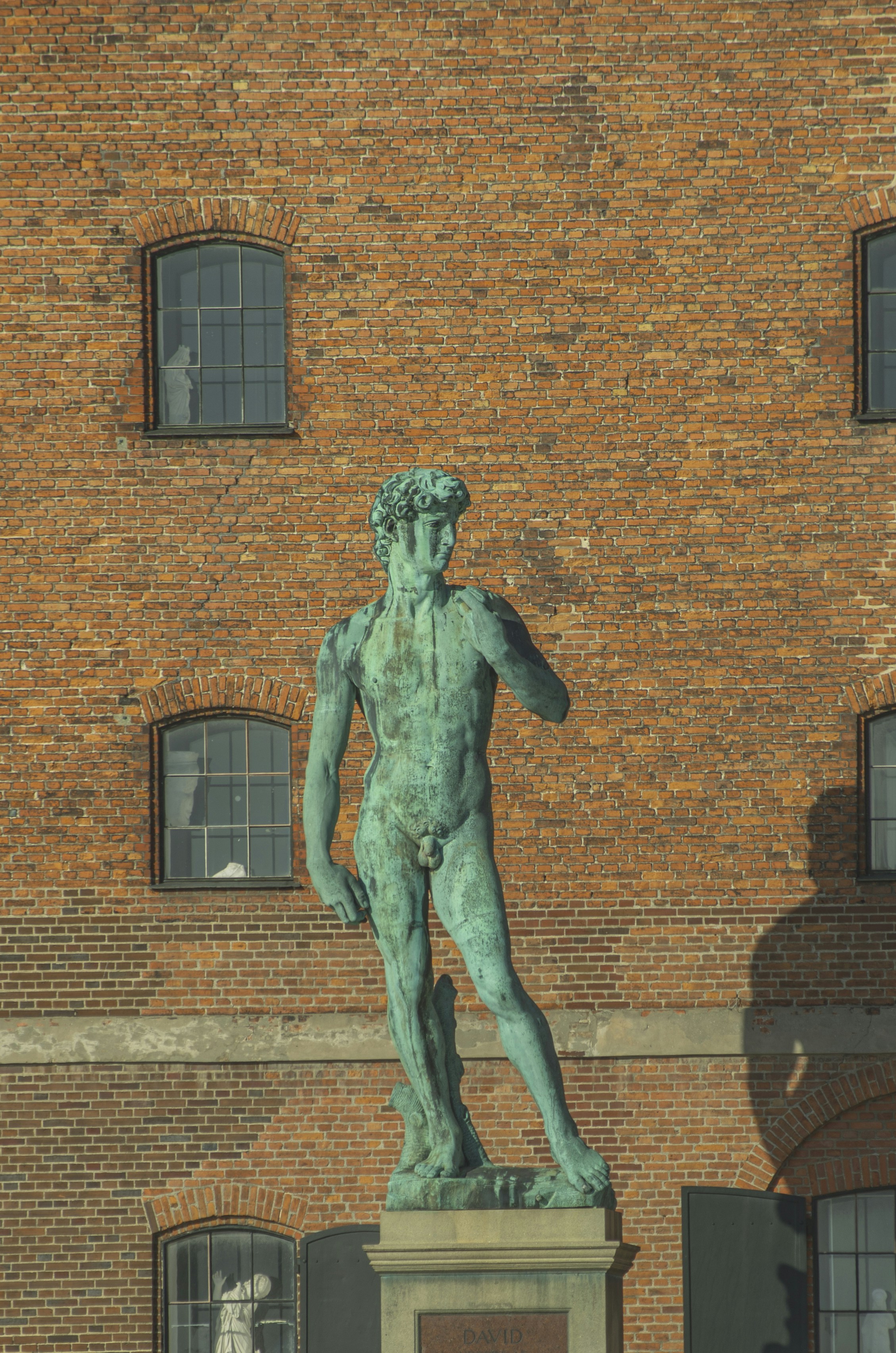 Bronze of David: Green Patina Against Red Brick