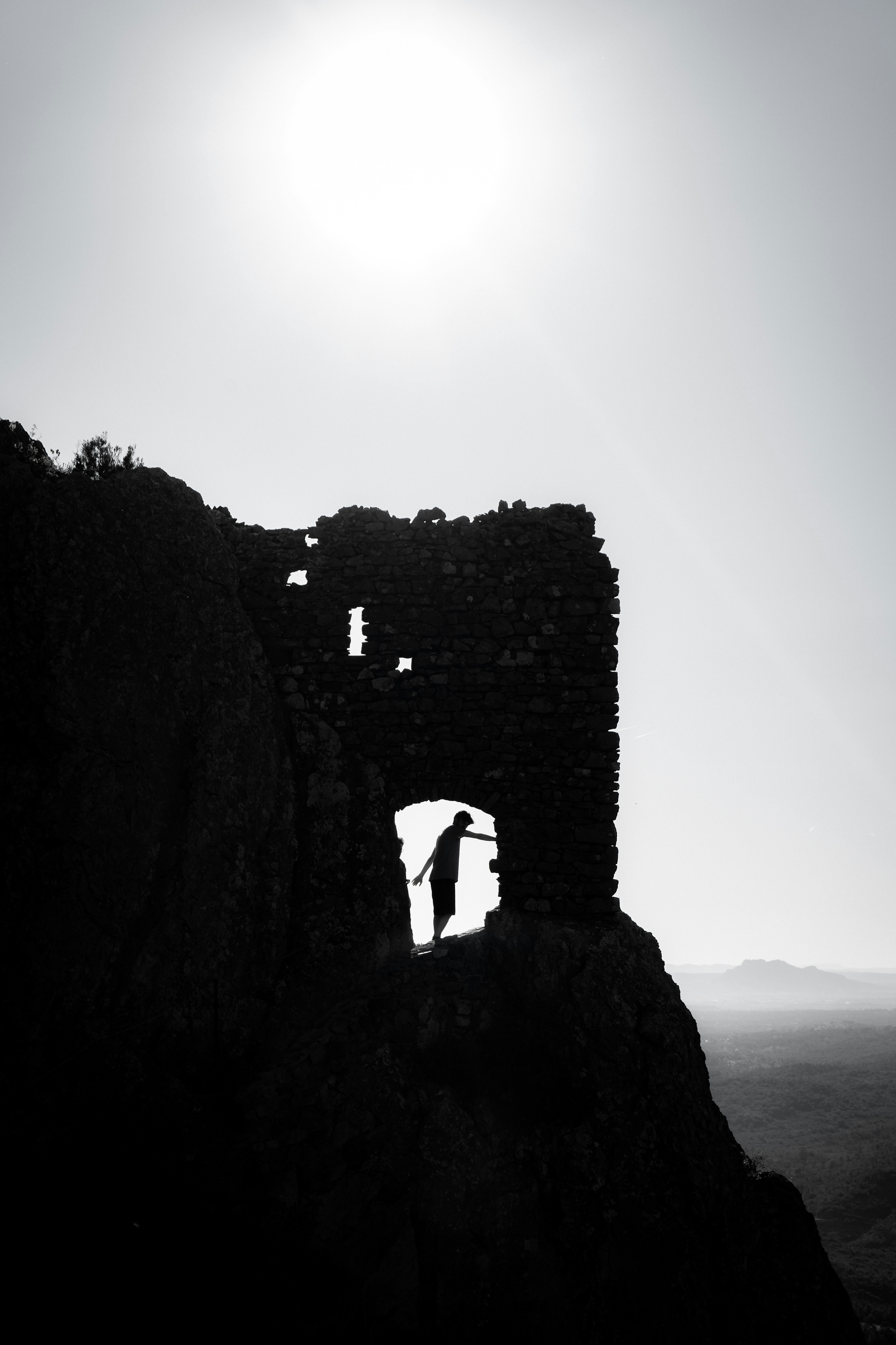 Silhouette atop Ruin: A Lone Wanderer Beneath a Blinding Sun