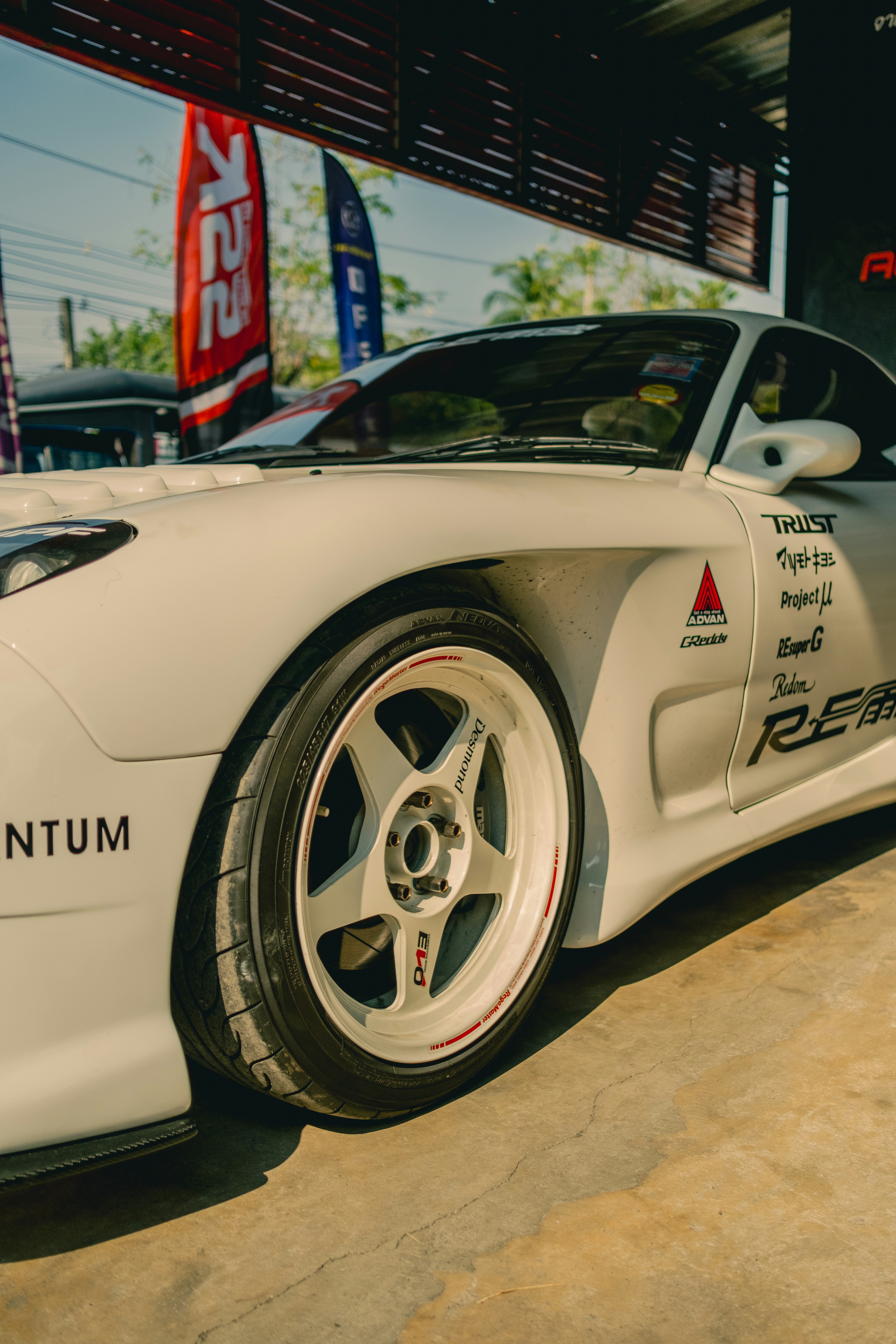 White Racecar at an Outdoor Show: Close-Up of Front Wheel and Sided decals
