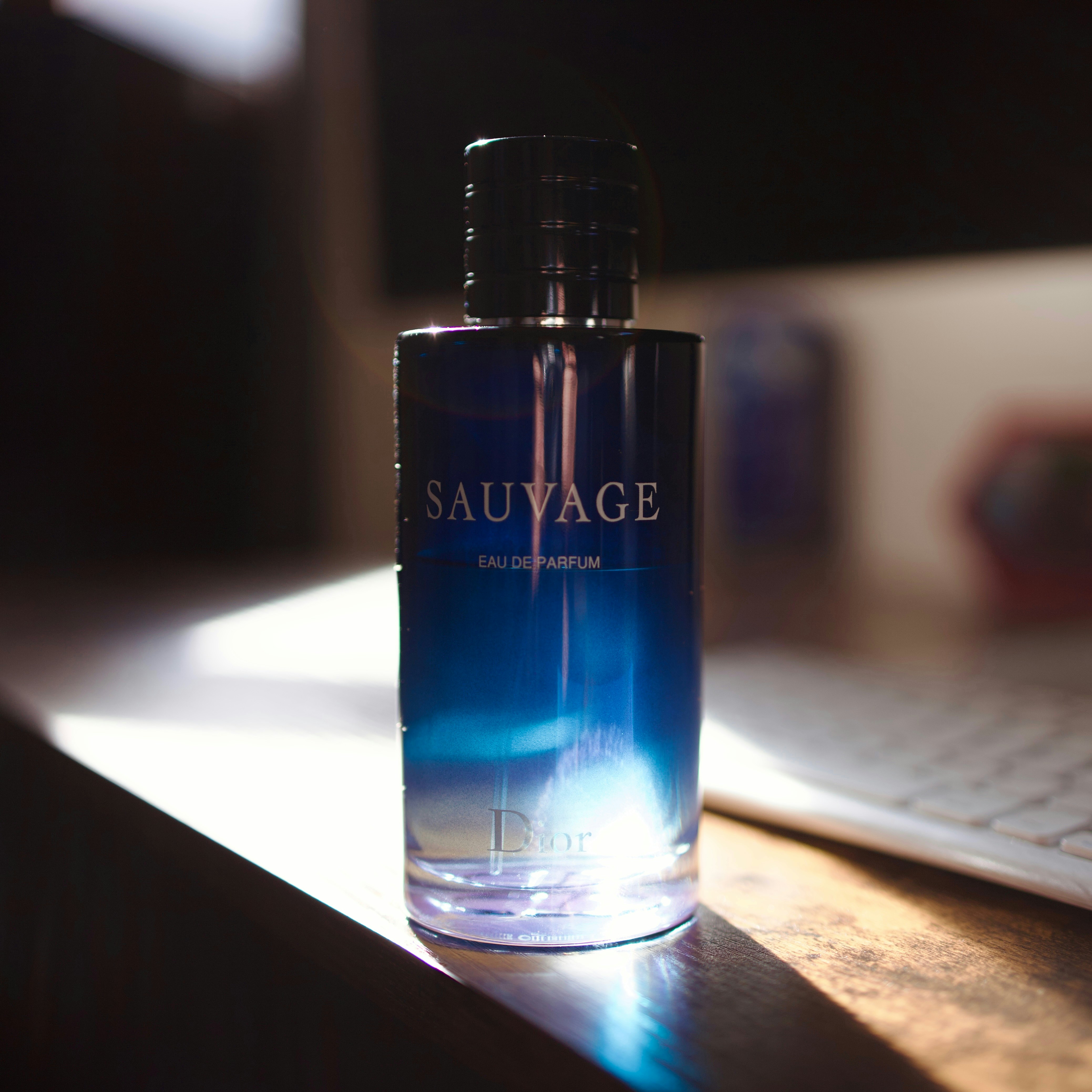 Scented Gradient: Blue Glass Perfume on Sunlit Desk