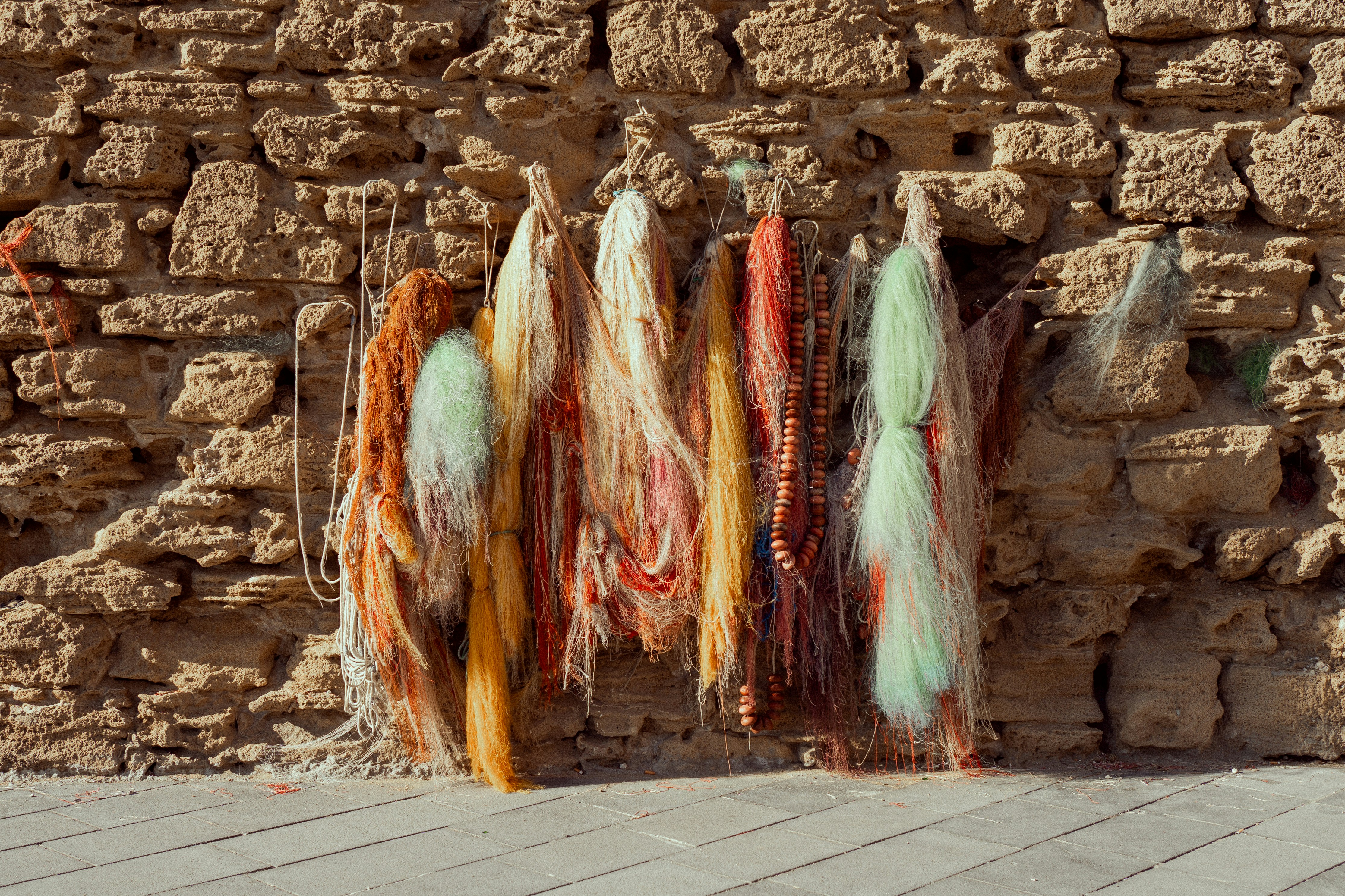 Hanging skeins against rustic stone: a study in color and texture