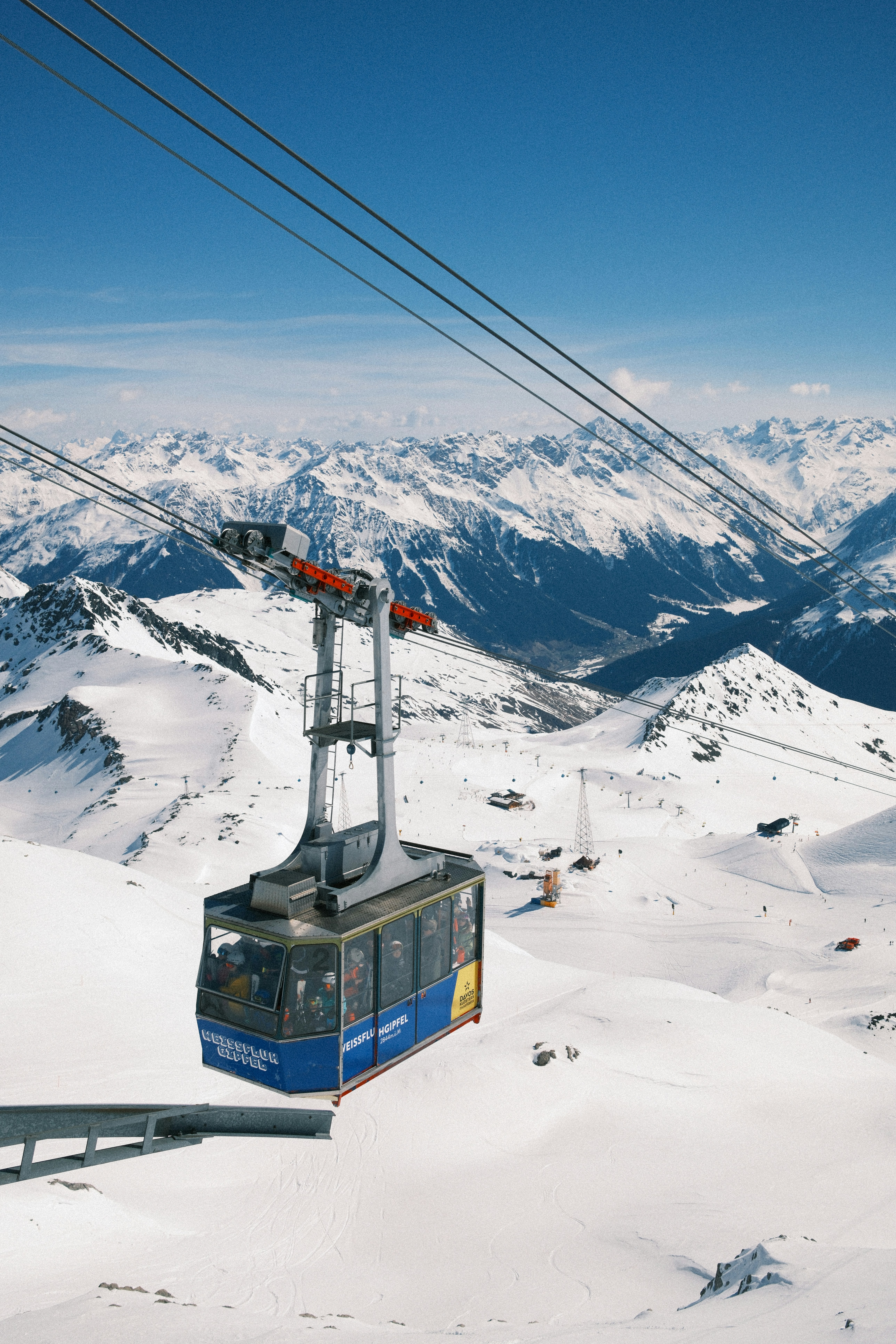 Snowbound Summit: A Gondola Climber Ascends Over the Alpine Expanse
