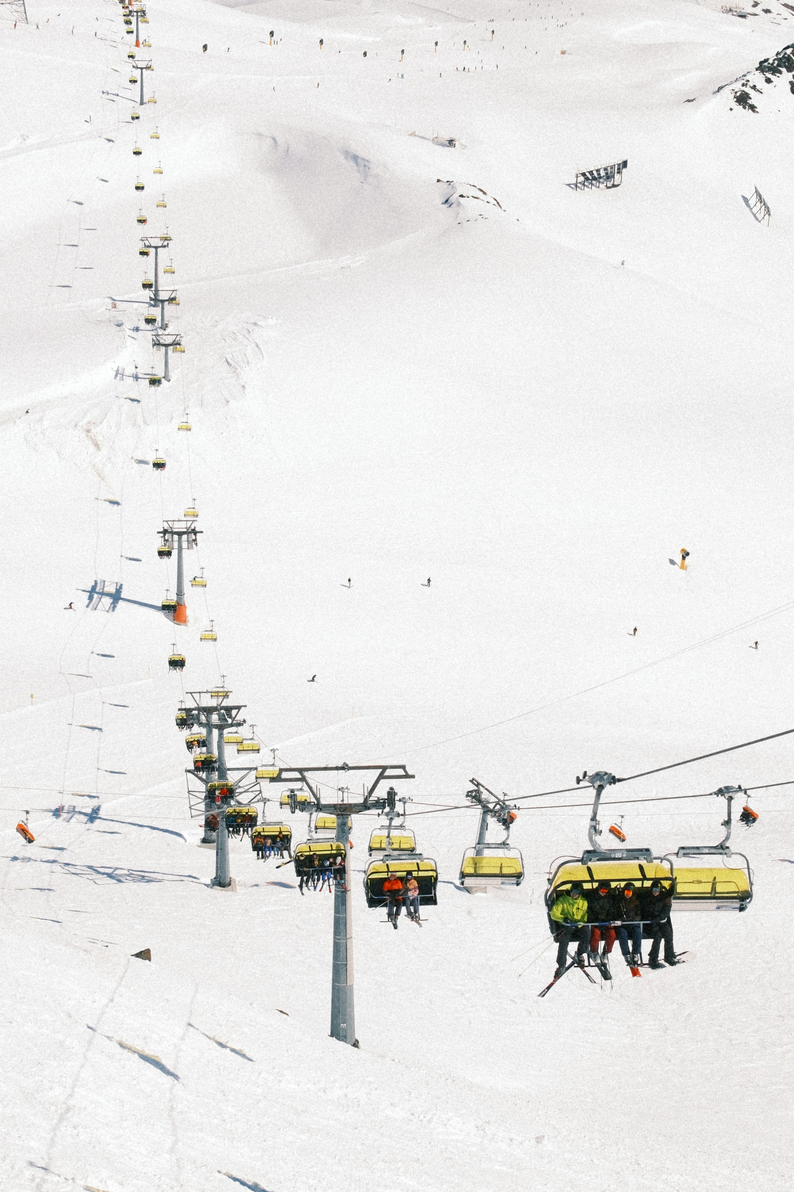 Snowbound Lift Ride: A Row of Yellow Chairs Climb a Quiet Alpine Slopes