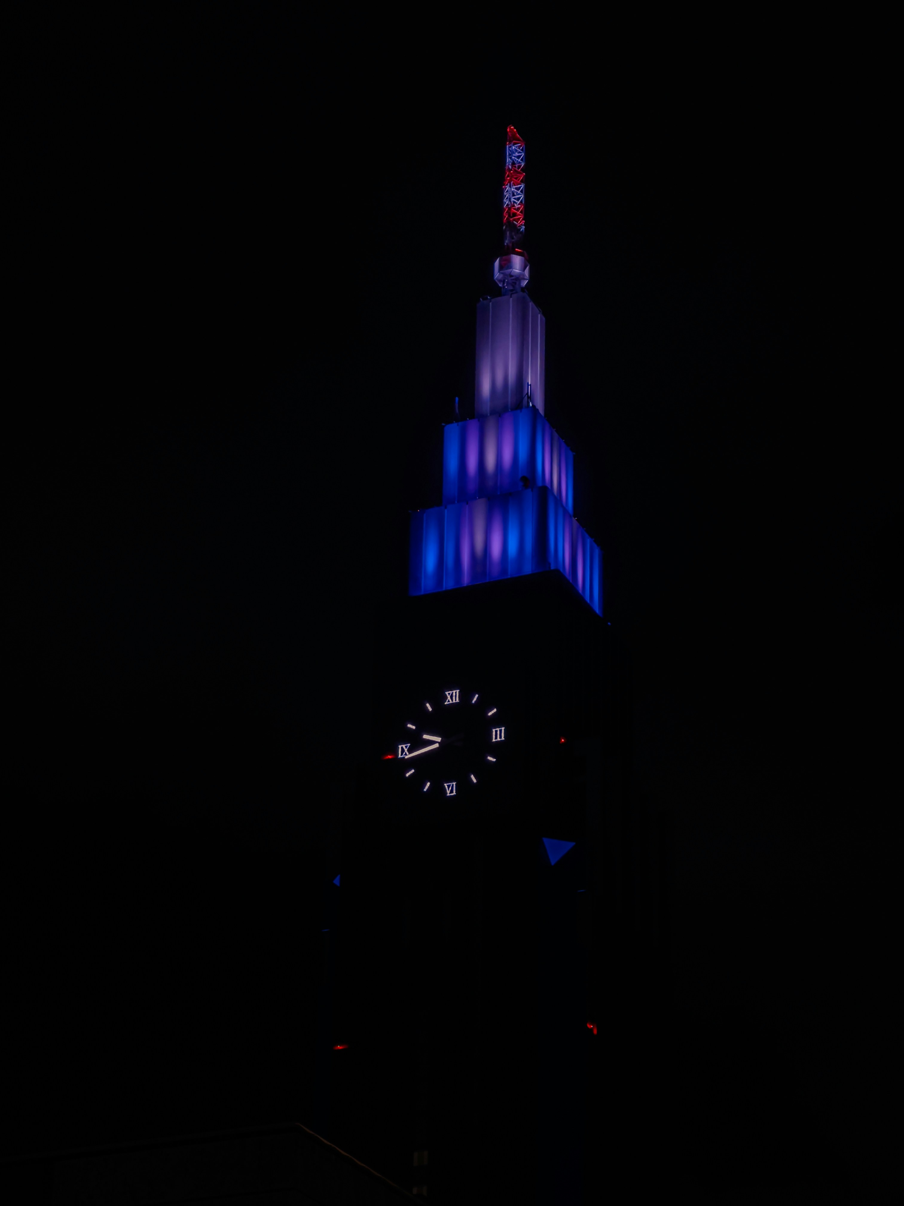Midnight Spire: Blue-Capped Clock Tower Rising from Darkness