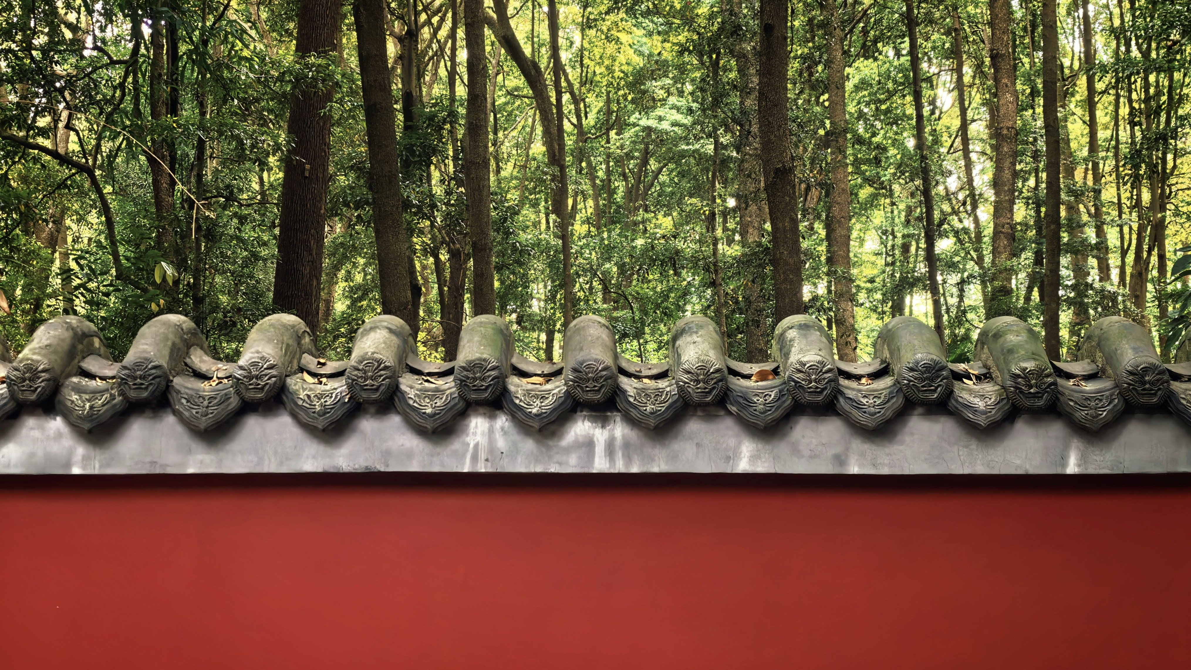 Guardians of the Gate: A Row of Roof Sculptures Over a Crimson Wall