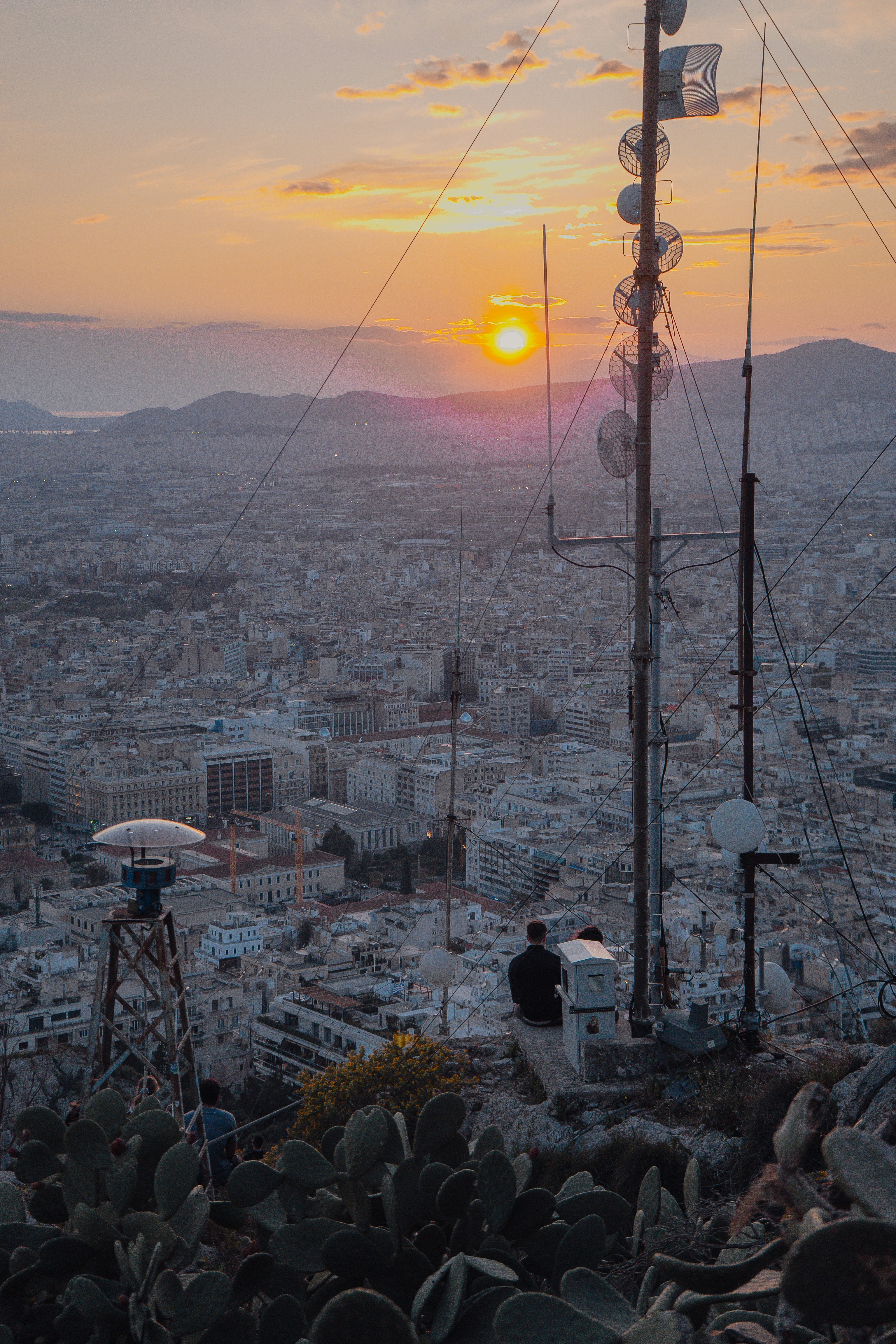 Rooftop Communications Tower Over a Sunset-Spread City