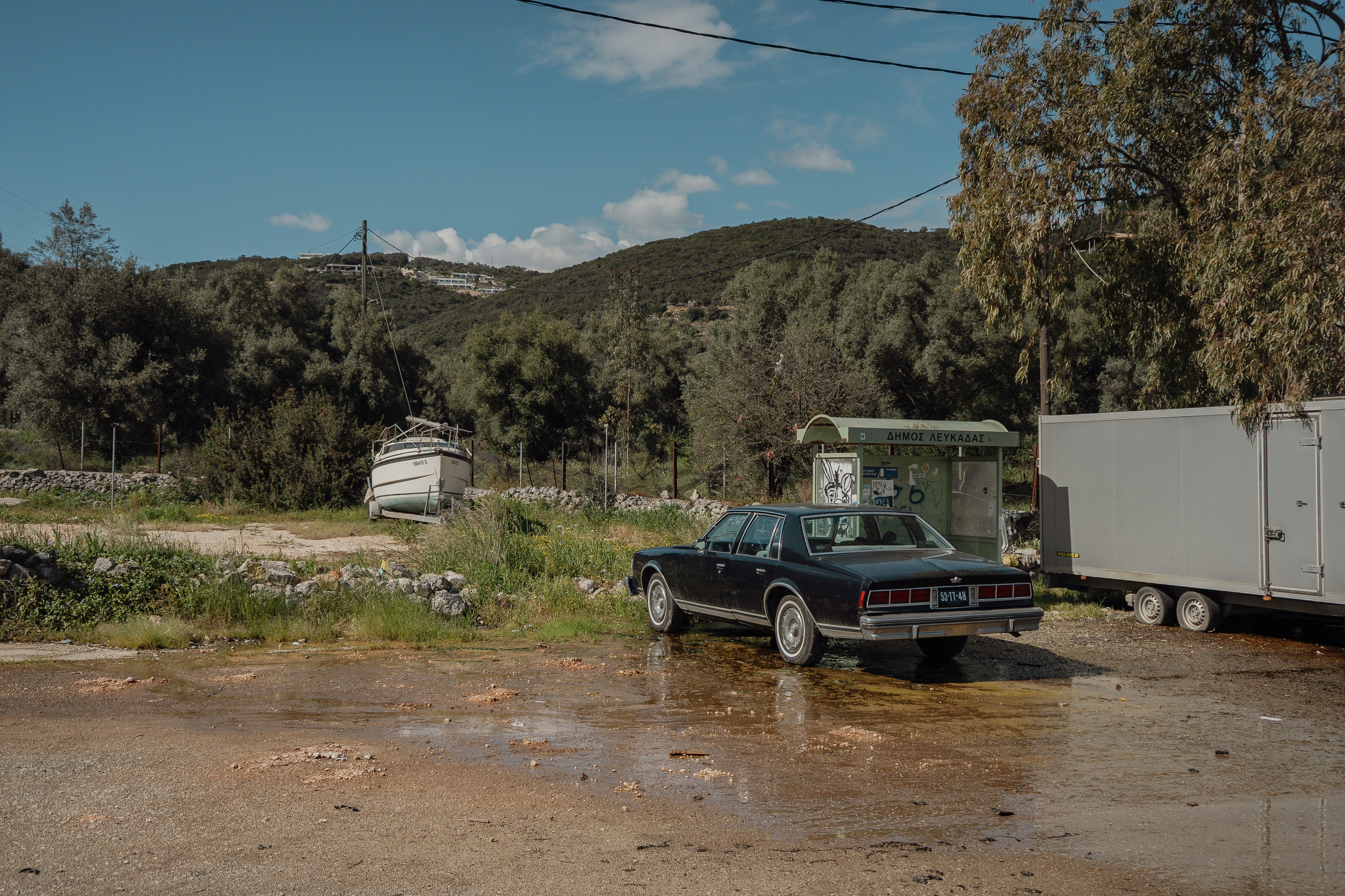 Midday Rendezvous: Classic Sedan by a Quiet Water-Resistant Lot