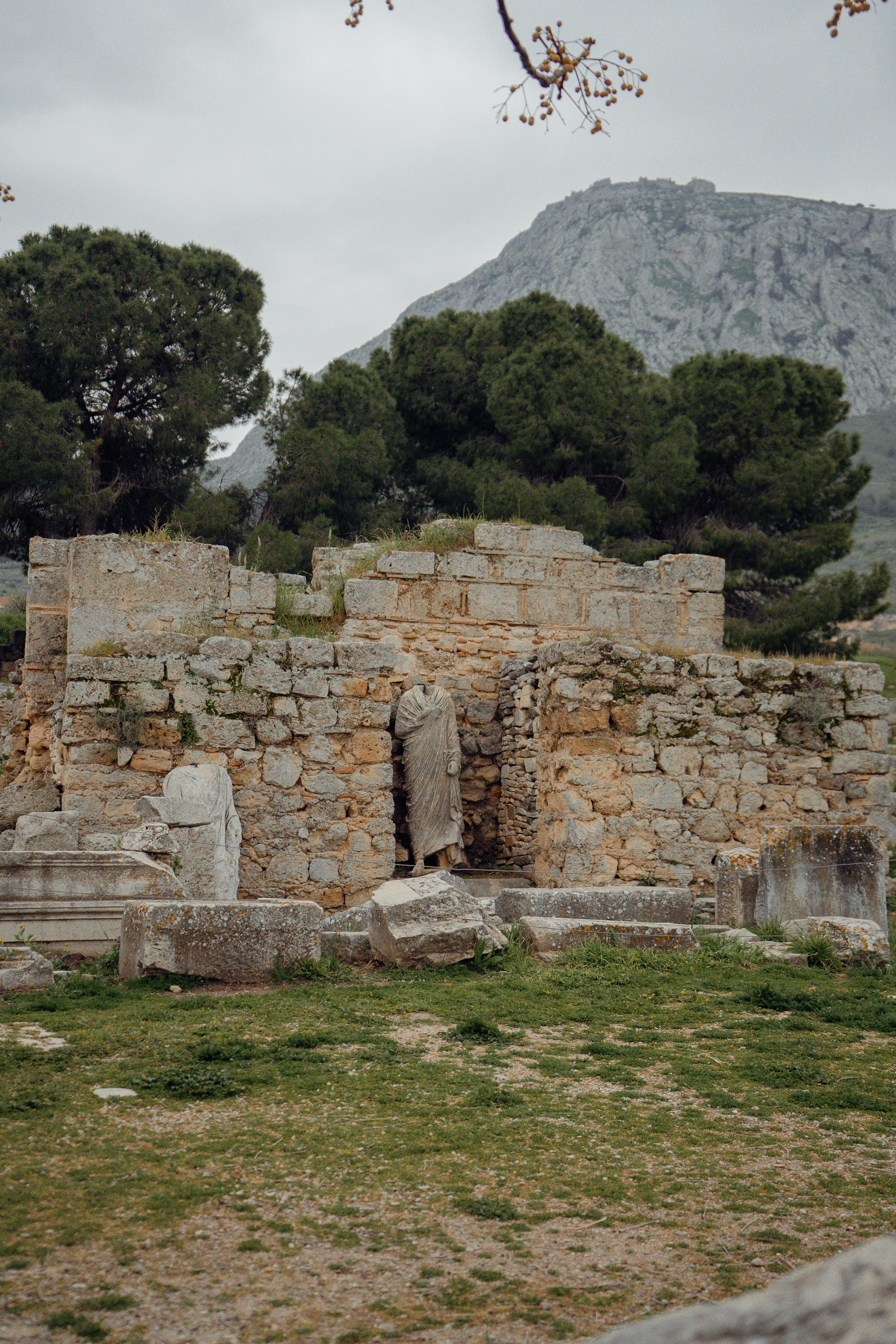 Ruins beneath the Mountain: A Silent Courtyard with Weathered Stone and Canopy of Pines