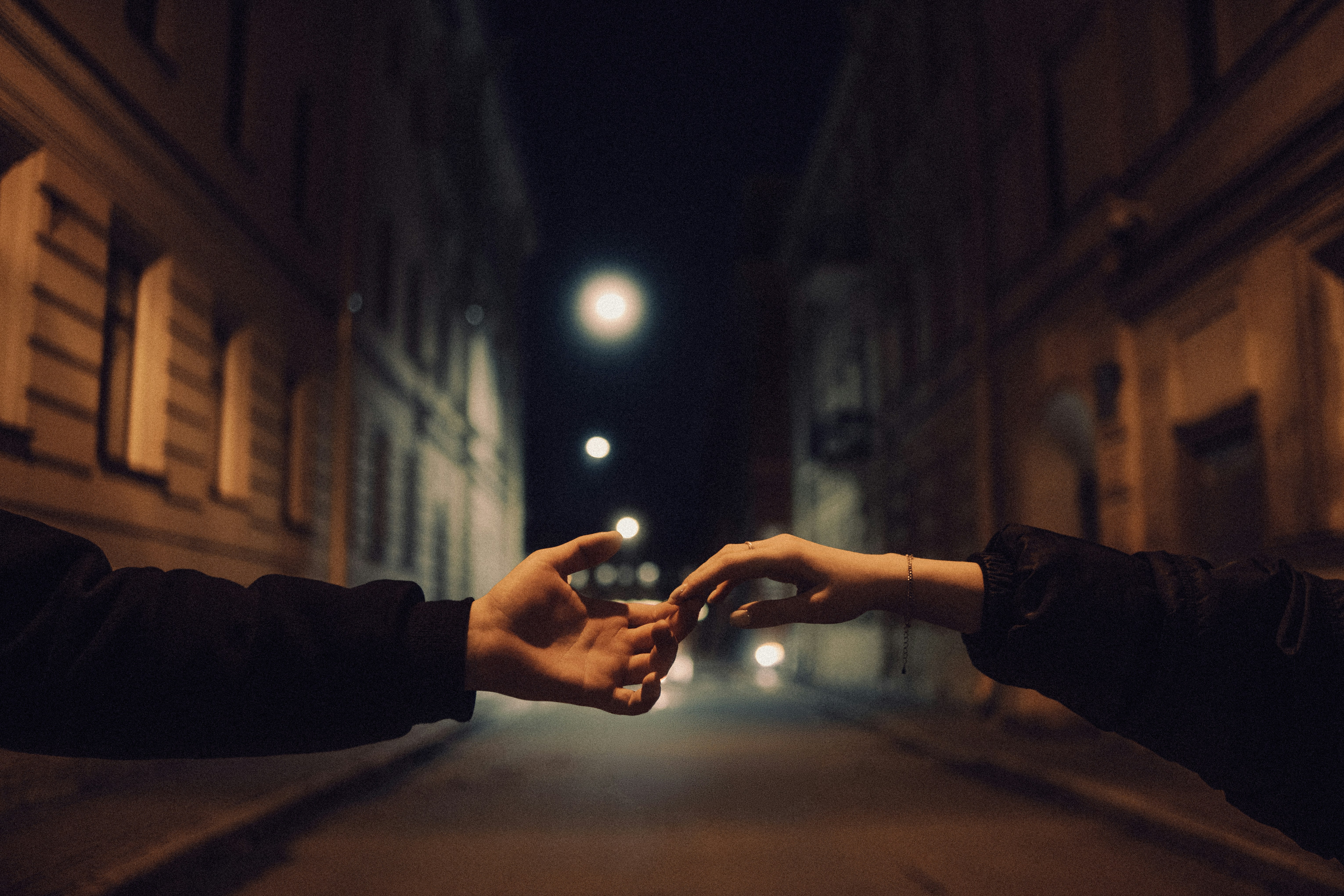 Midnight reach: a quiet bridge of fingers in a dim alley