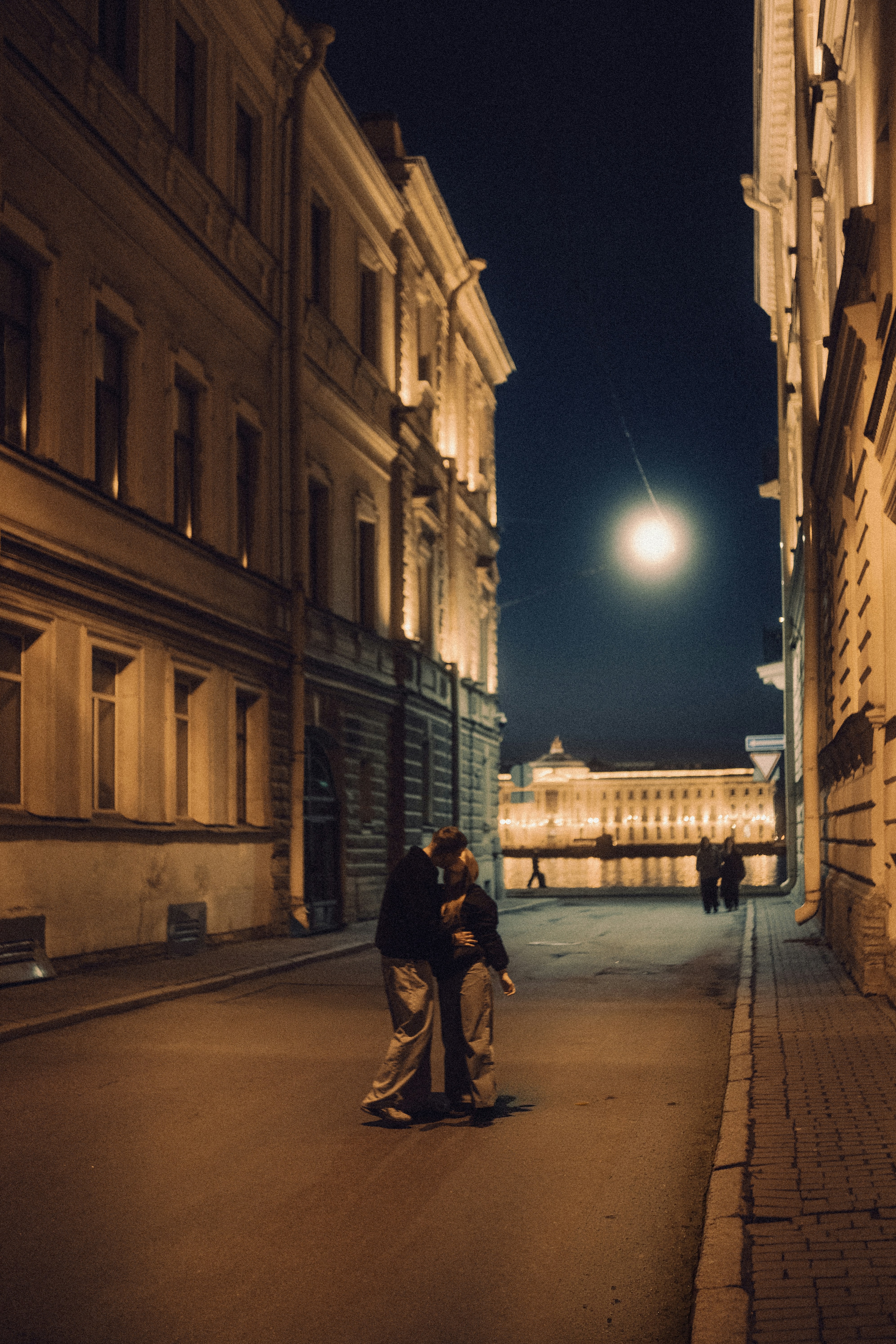 Night stroll by the illuminated canal courts a quiet embrace