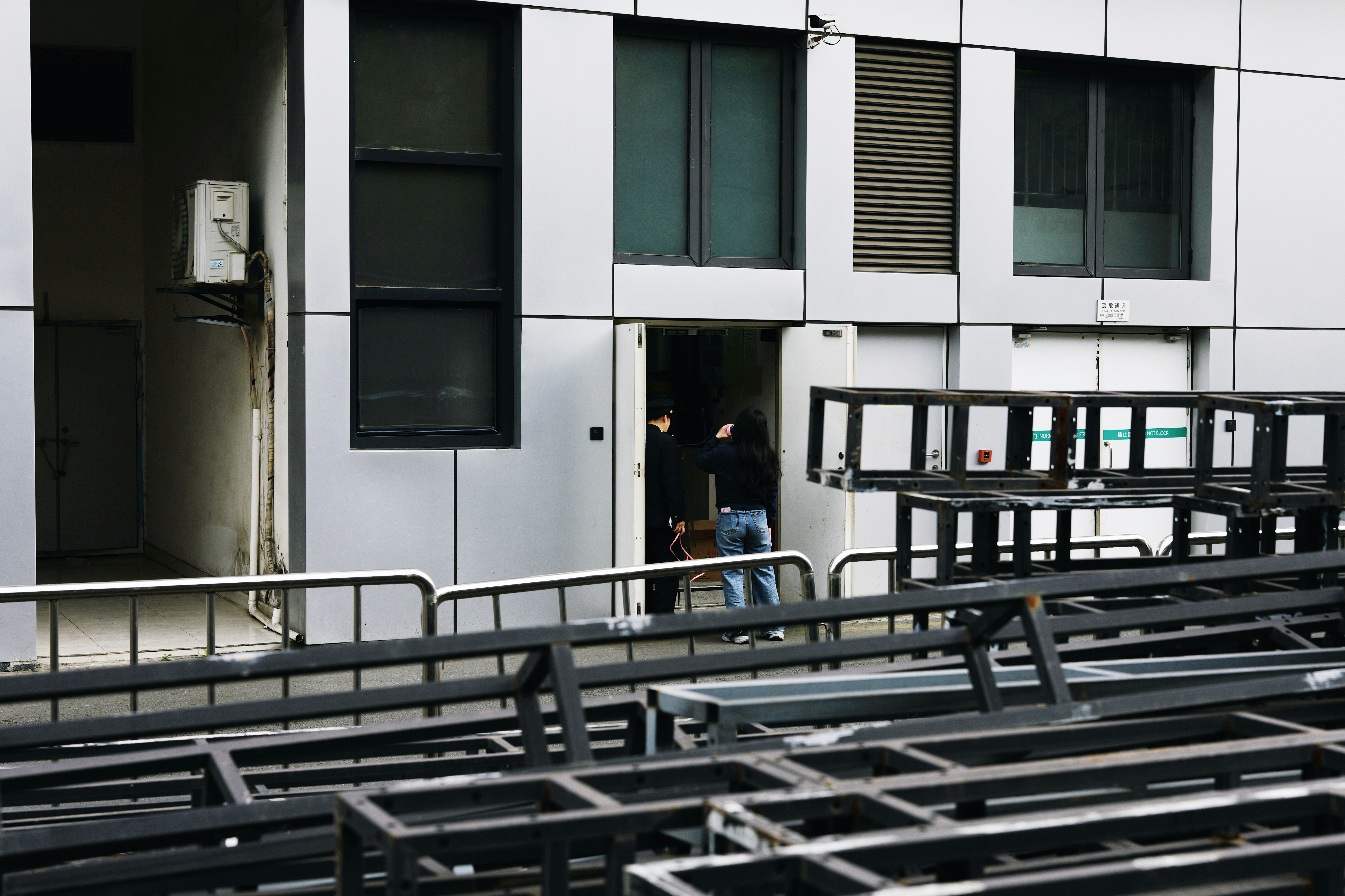 Urban doorway: two figures at the entrance amid a tangle of rooftop scaffolding