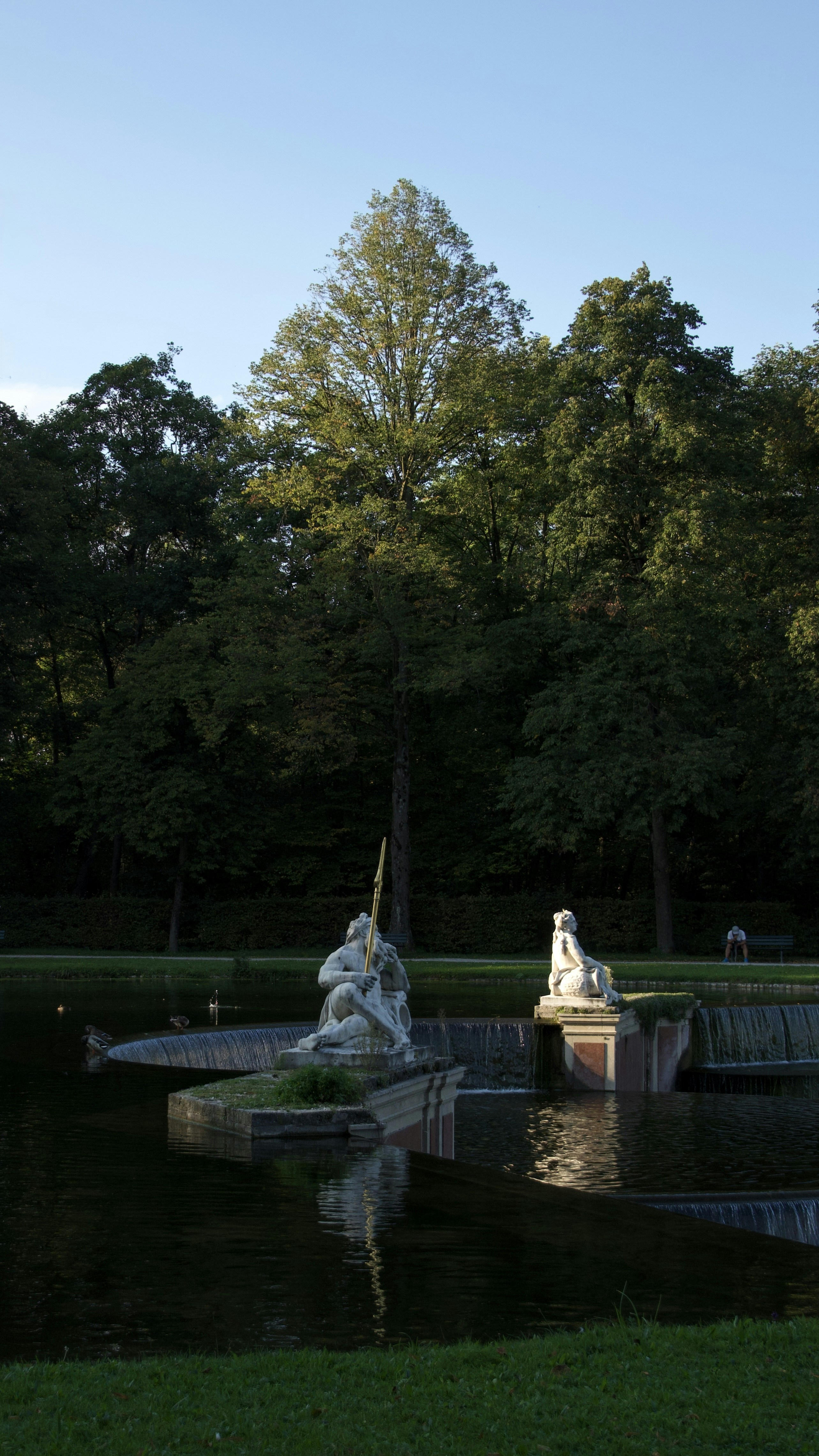 Statues and a Central Tree Framed by a Quiet Park Pond
