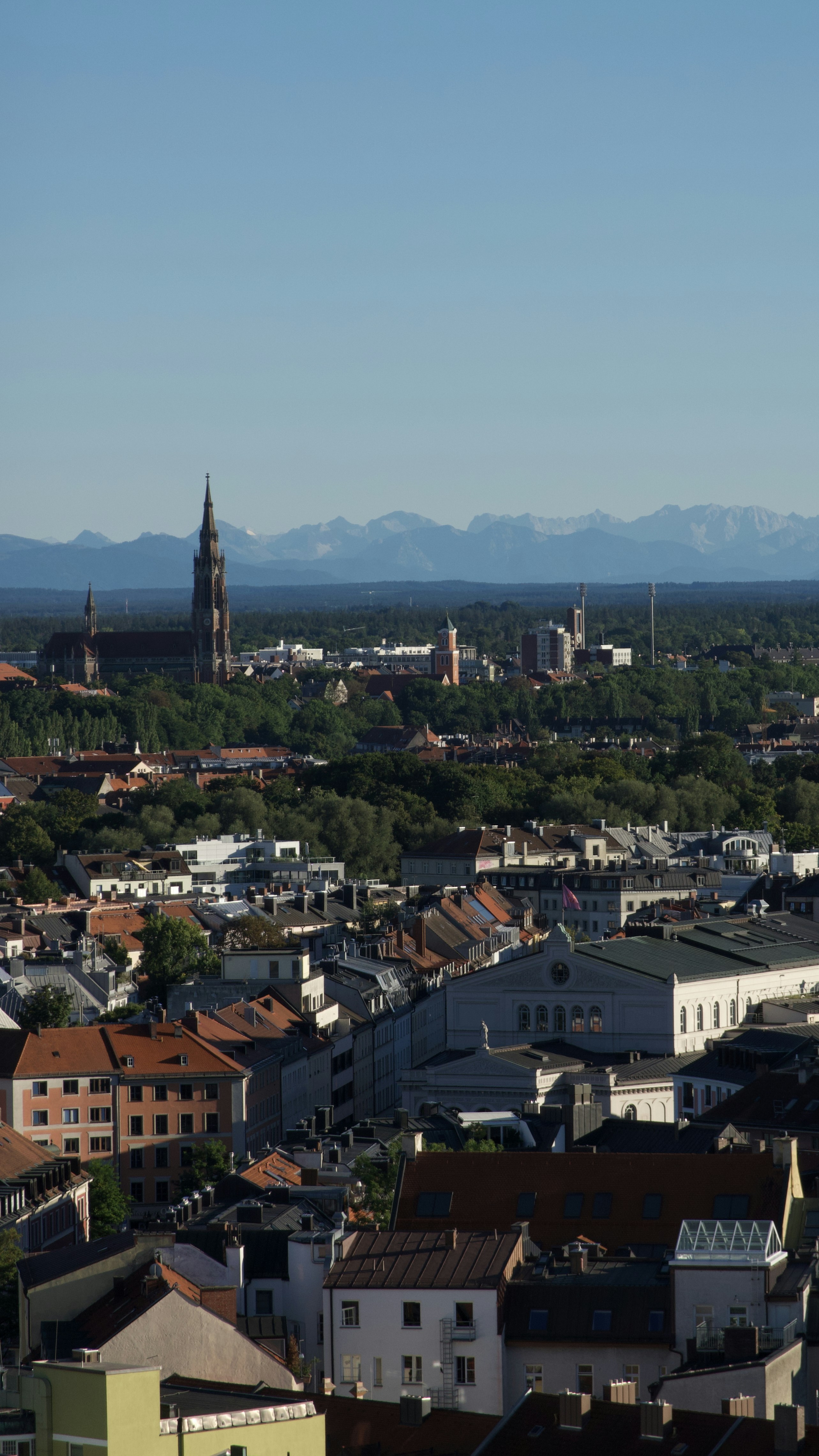 Spire Over the Rooftops: A Panoramic Citywith Alpine Backdrop