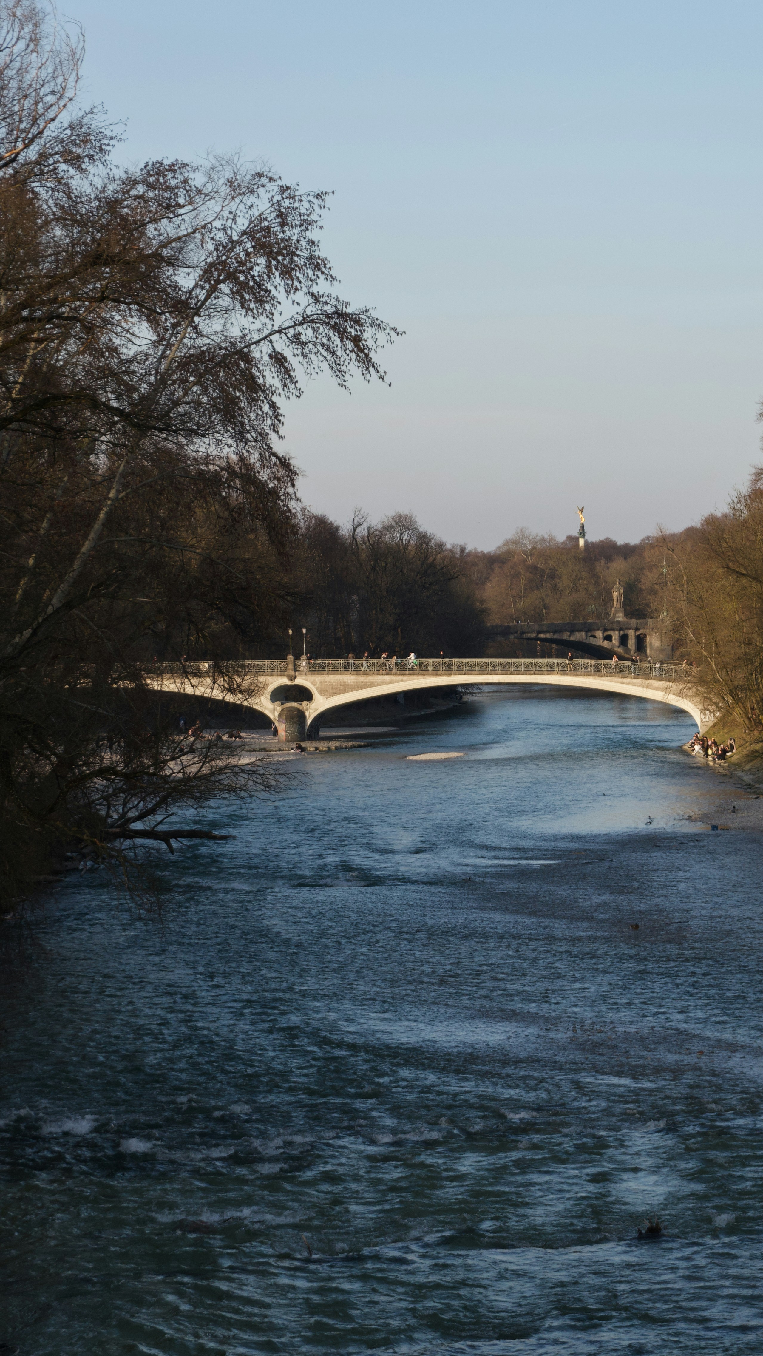 Evening River Arc: A Quiet City Bridge Framed by Bare Trees