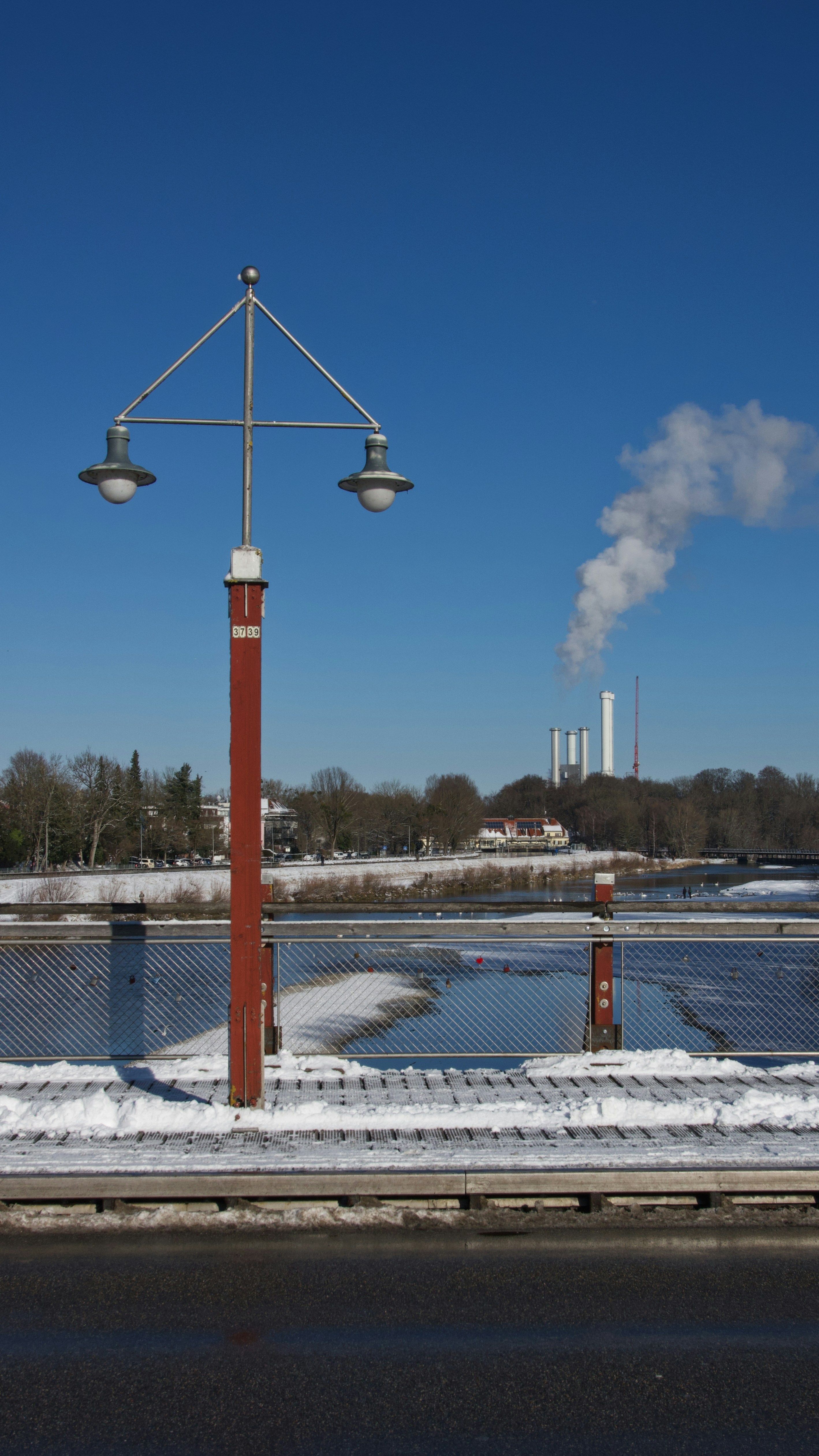 Streetlamp Sentinel Over Snow-Covered Riverfront
