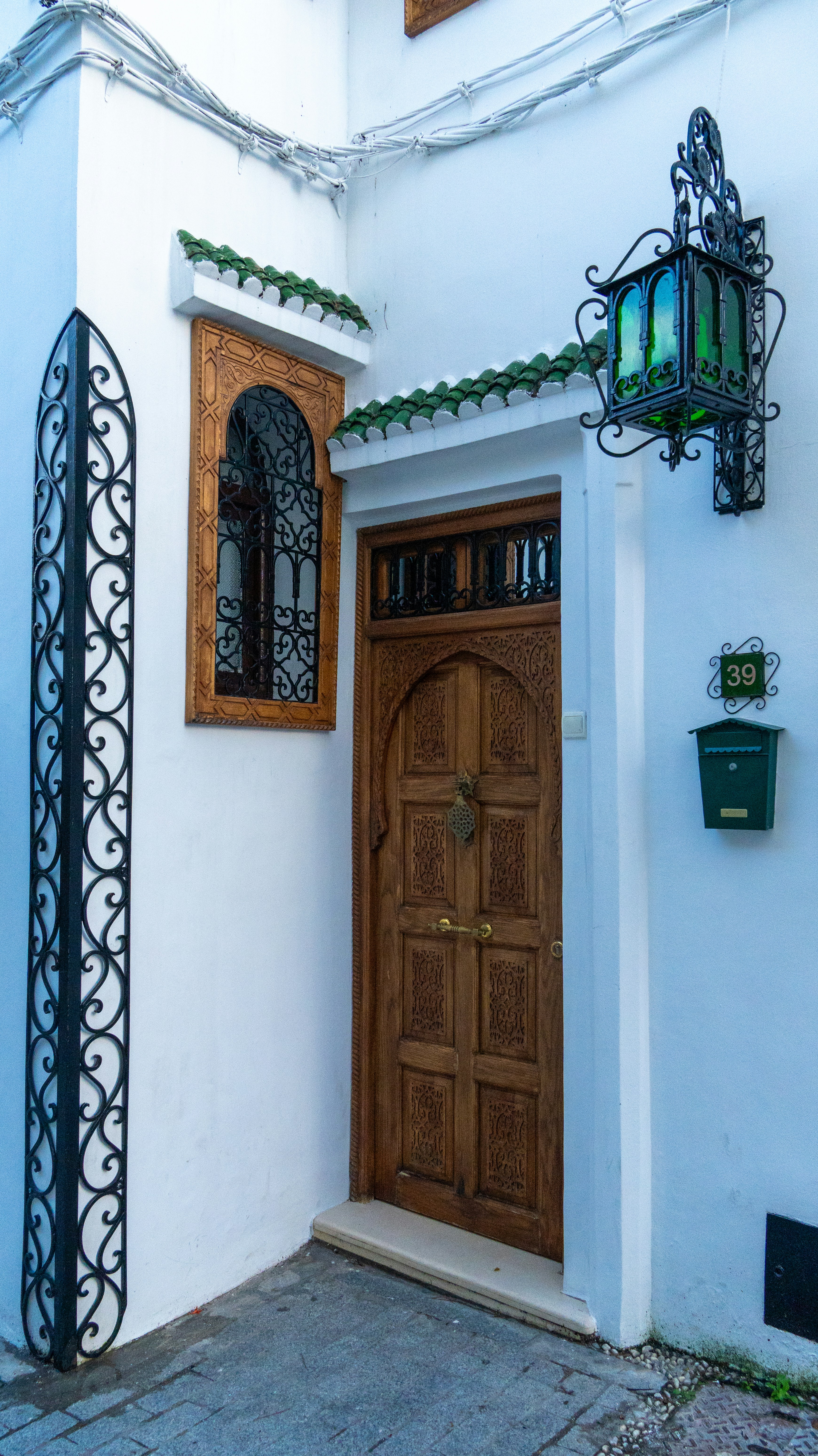 Carved door and turquoise lantern at sunlit white-washed doorway
