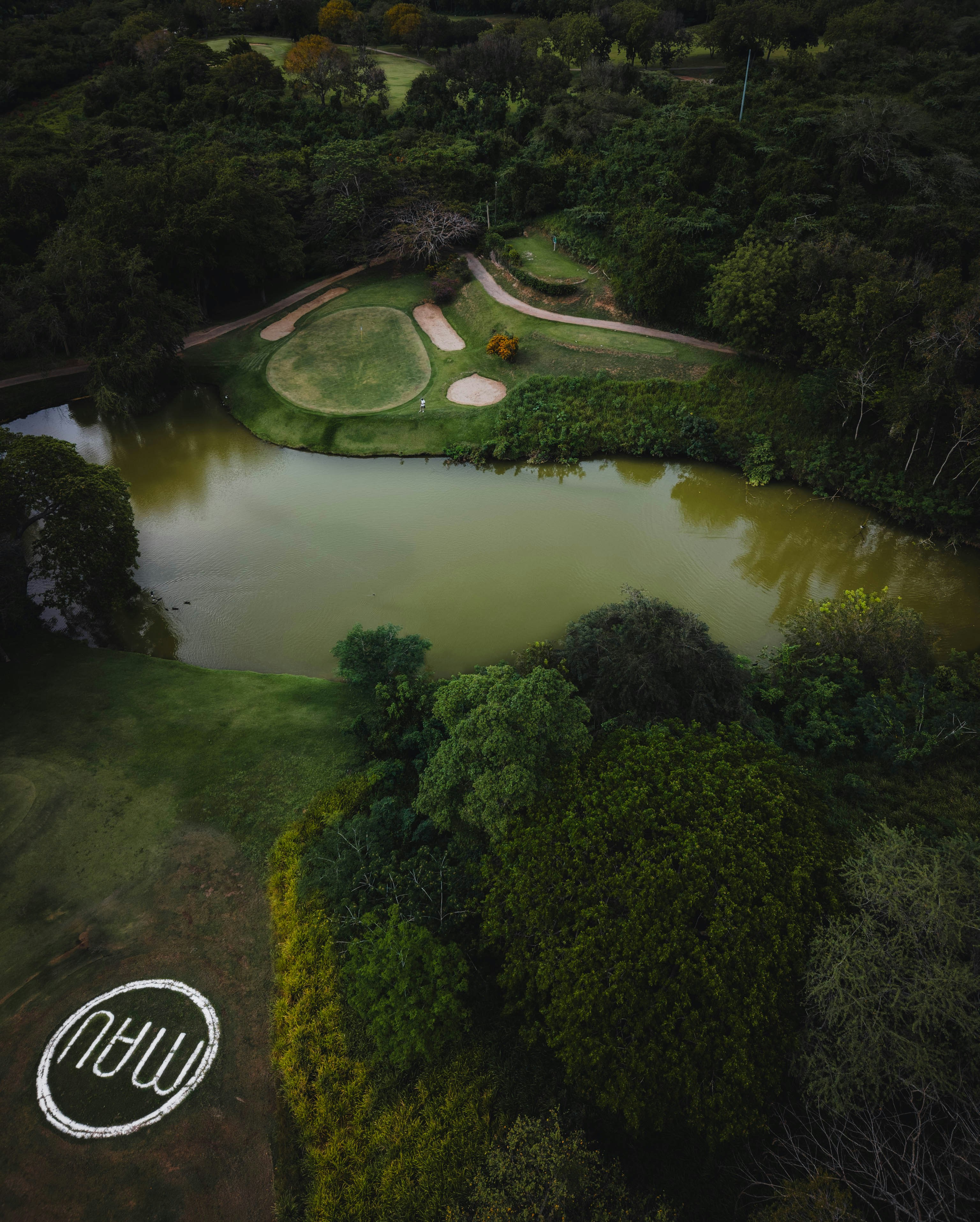 Aerial View into a Serene Golf Hole Bordered by Water and Trees