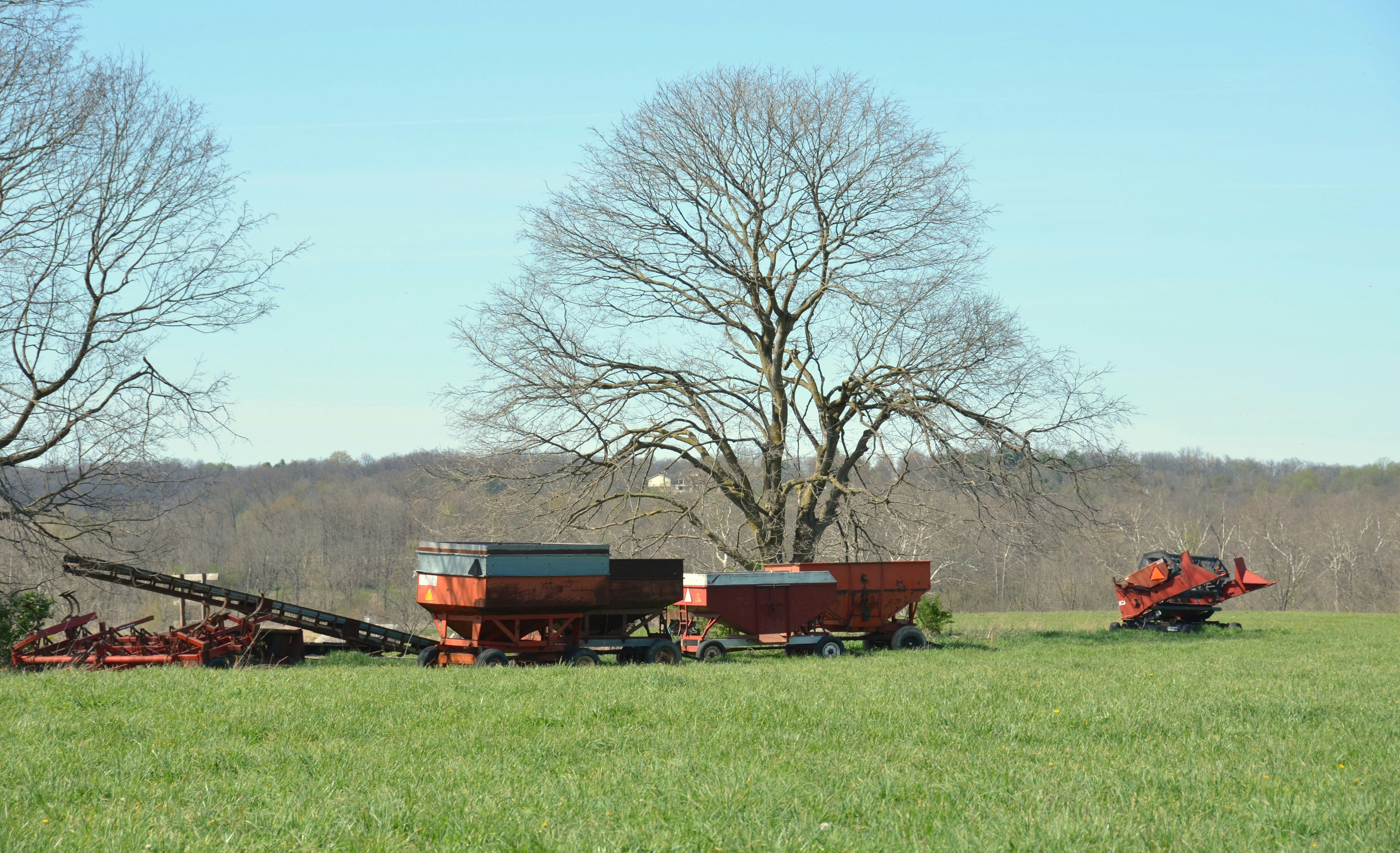 Midfield Harvest: Red Equipment Resting Under a Benign Blue Sky