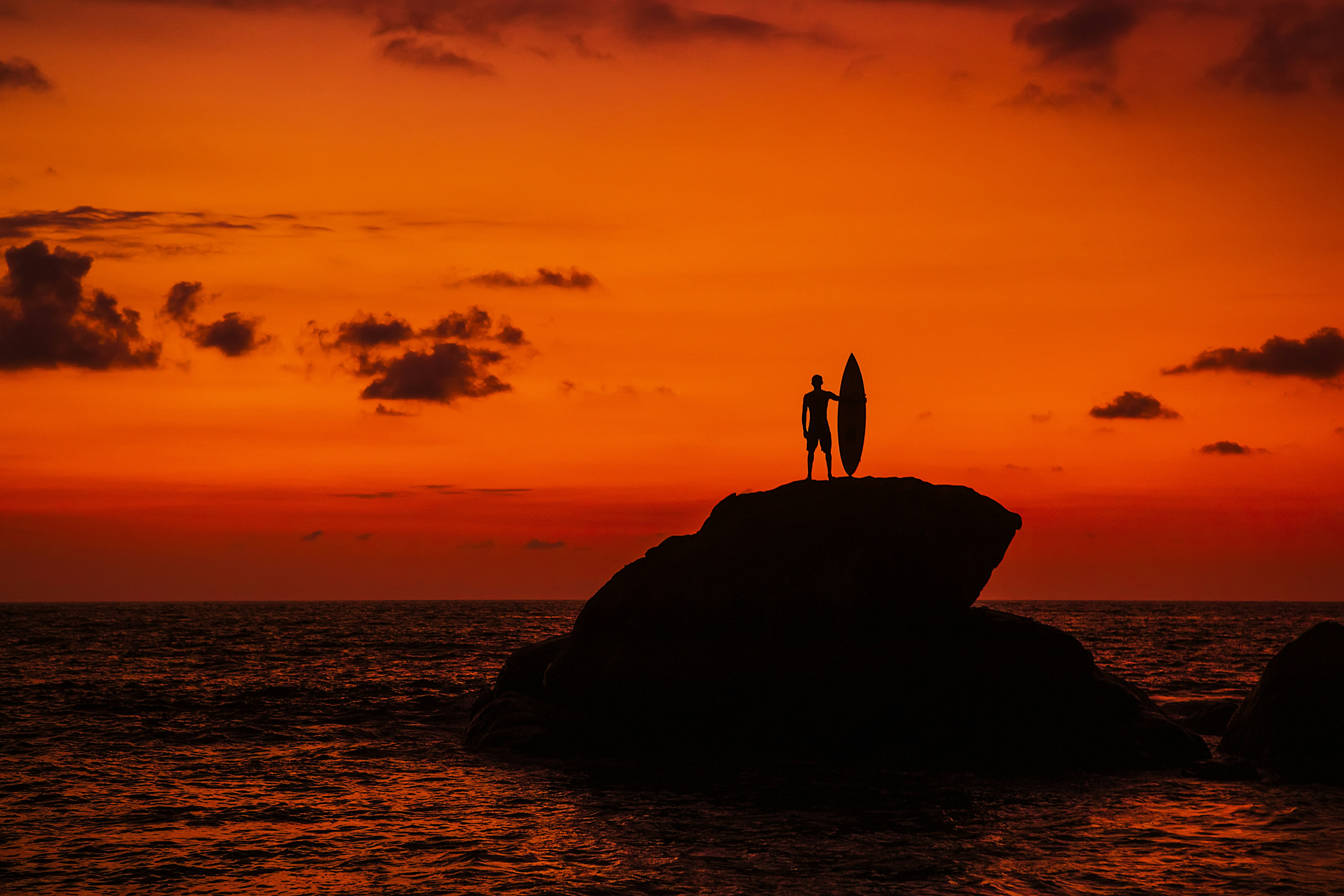 Silhouetted Surfer on a Sunset Cliff