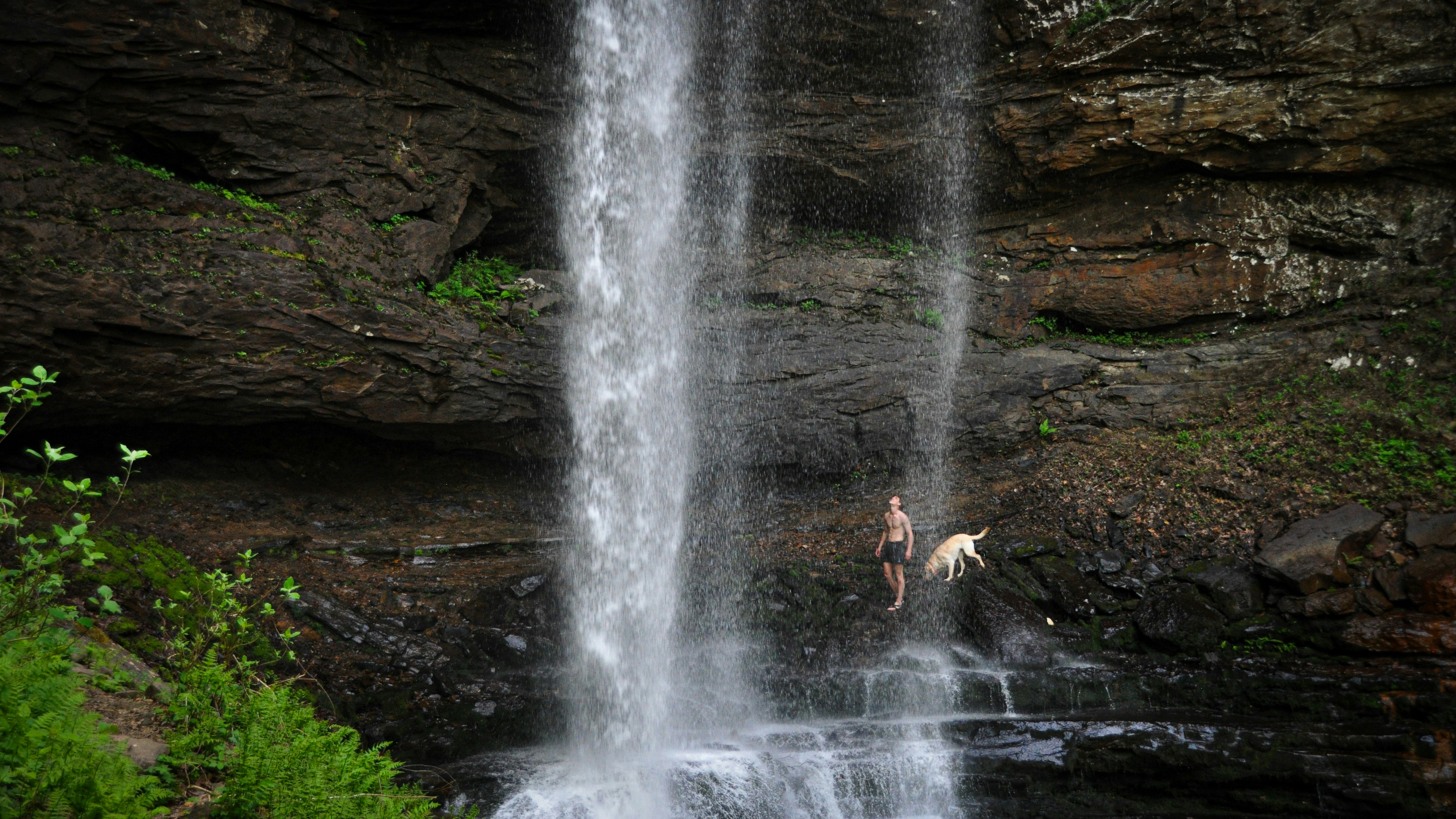 Cascading Veil: Narrow Falls Behind a Cliffside Platform