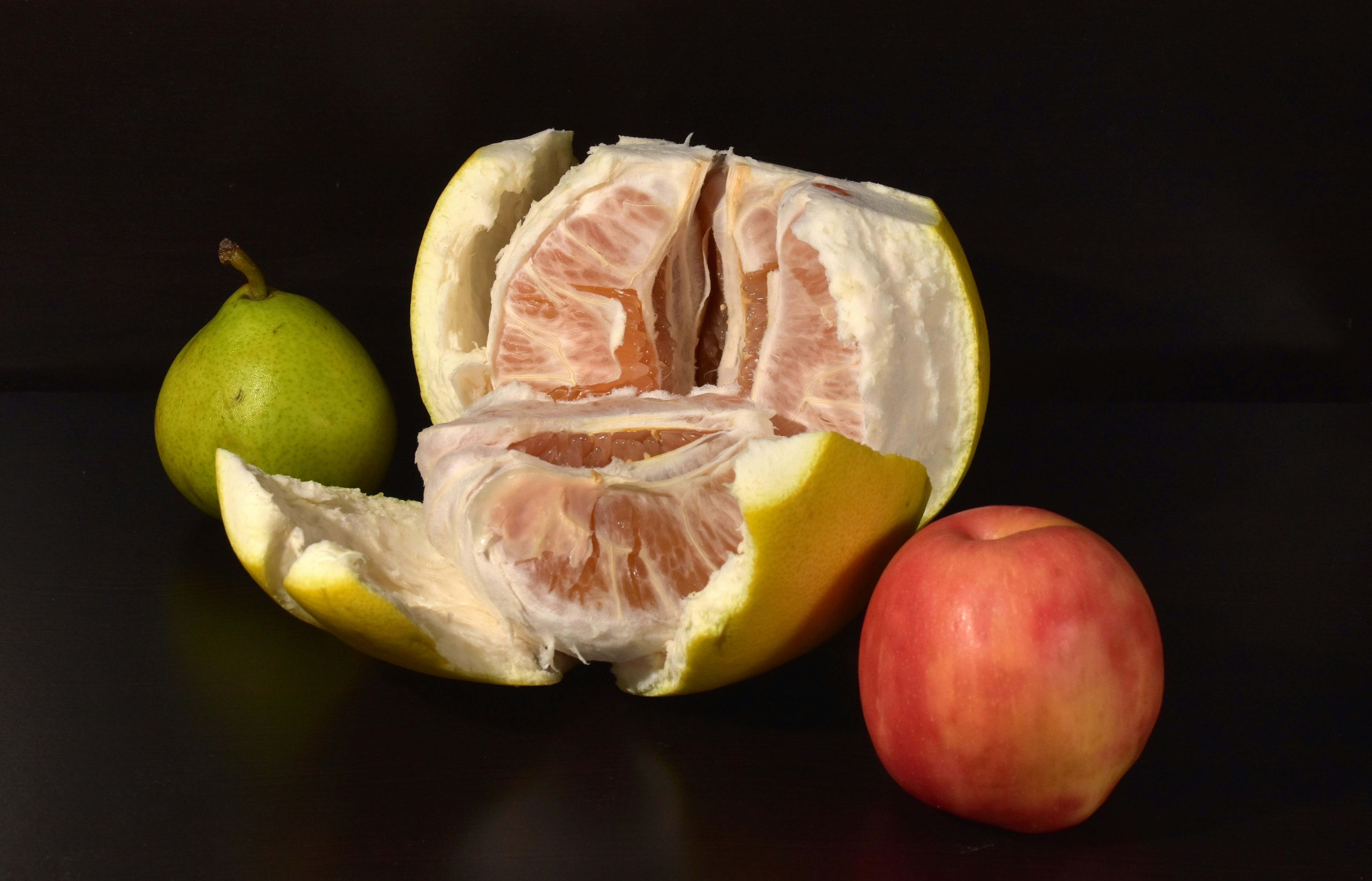 Split Citrus Still Life: A Pear, Grapefruit, and Apple Rest on a Velvet Darkness