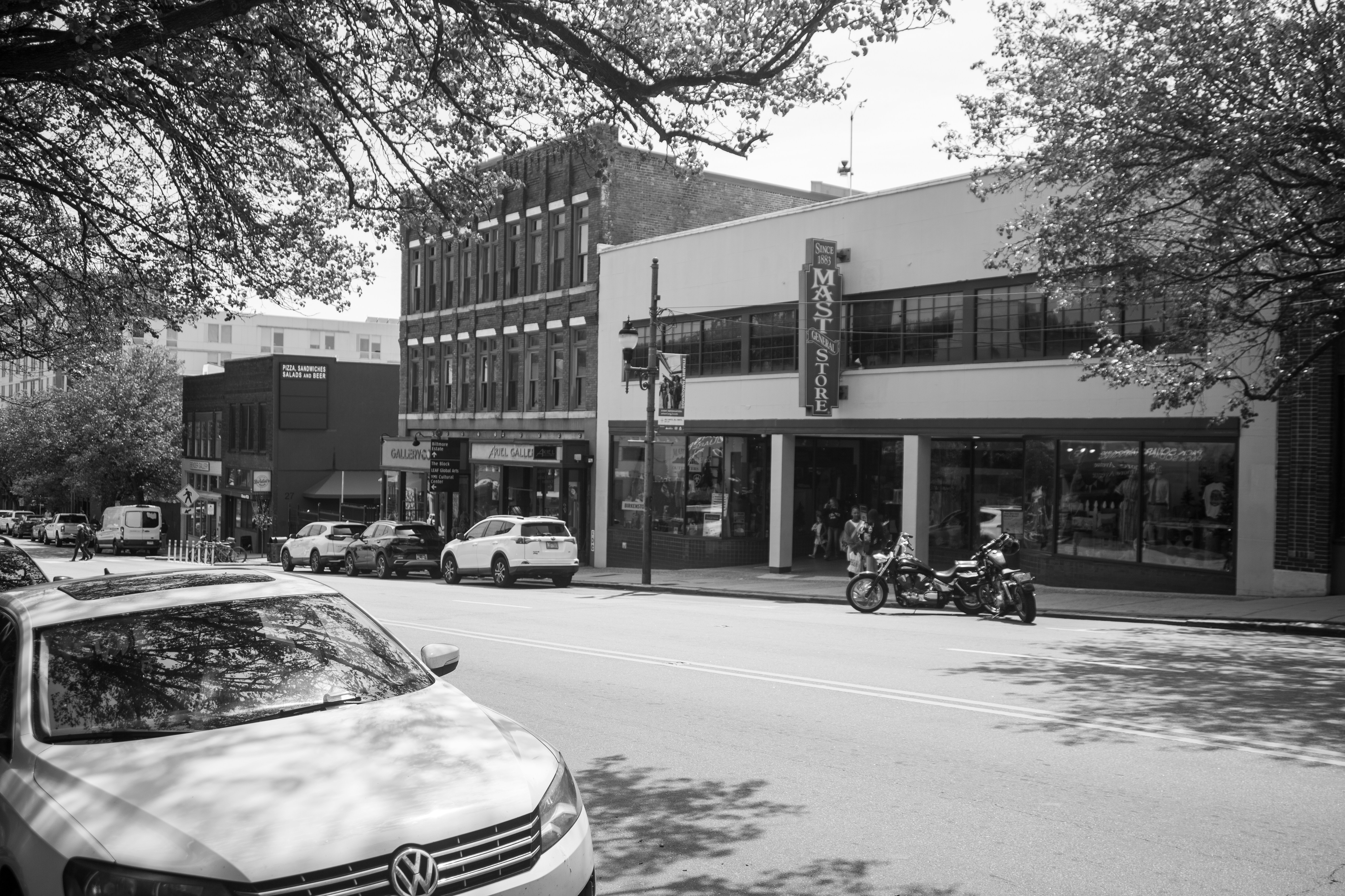 Streetfront in monochrome: cars, cyclists, and a vintage storefront