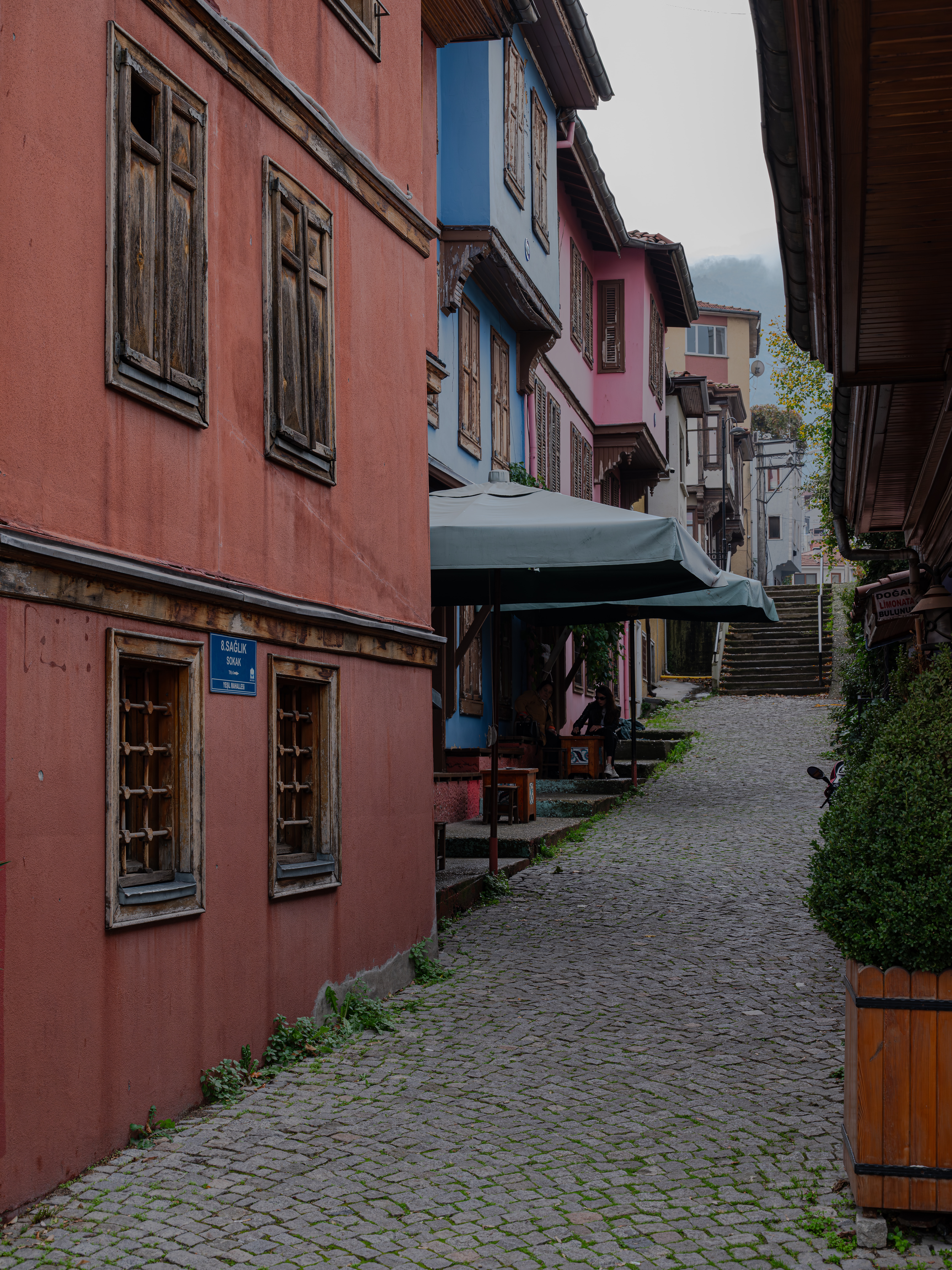 Colorful hillside alleyway with cobblestones and shaded cafe