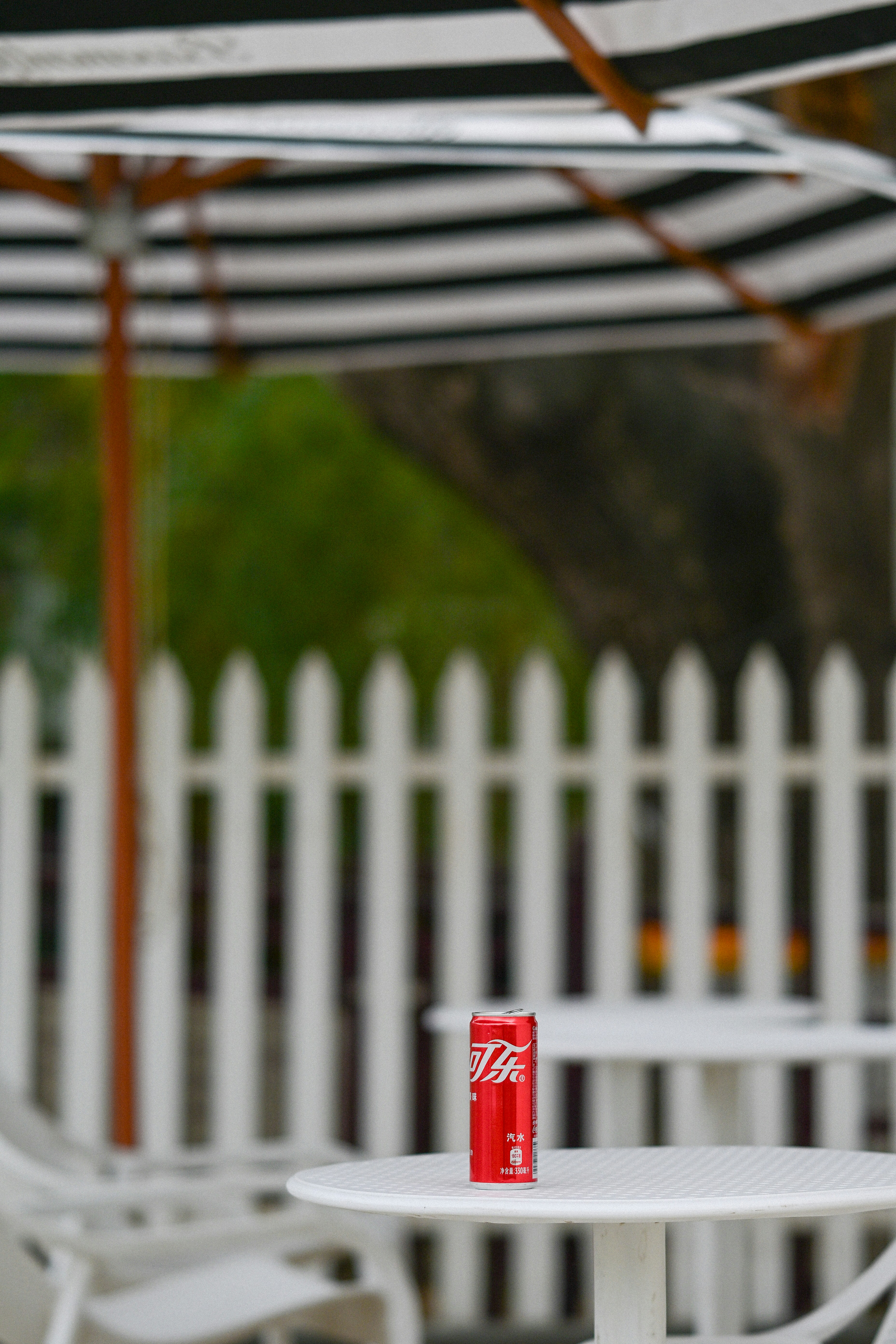 Red Can on White Table: Quiet Moment Under Striped Shade
