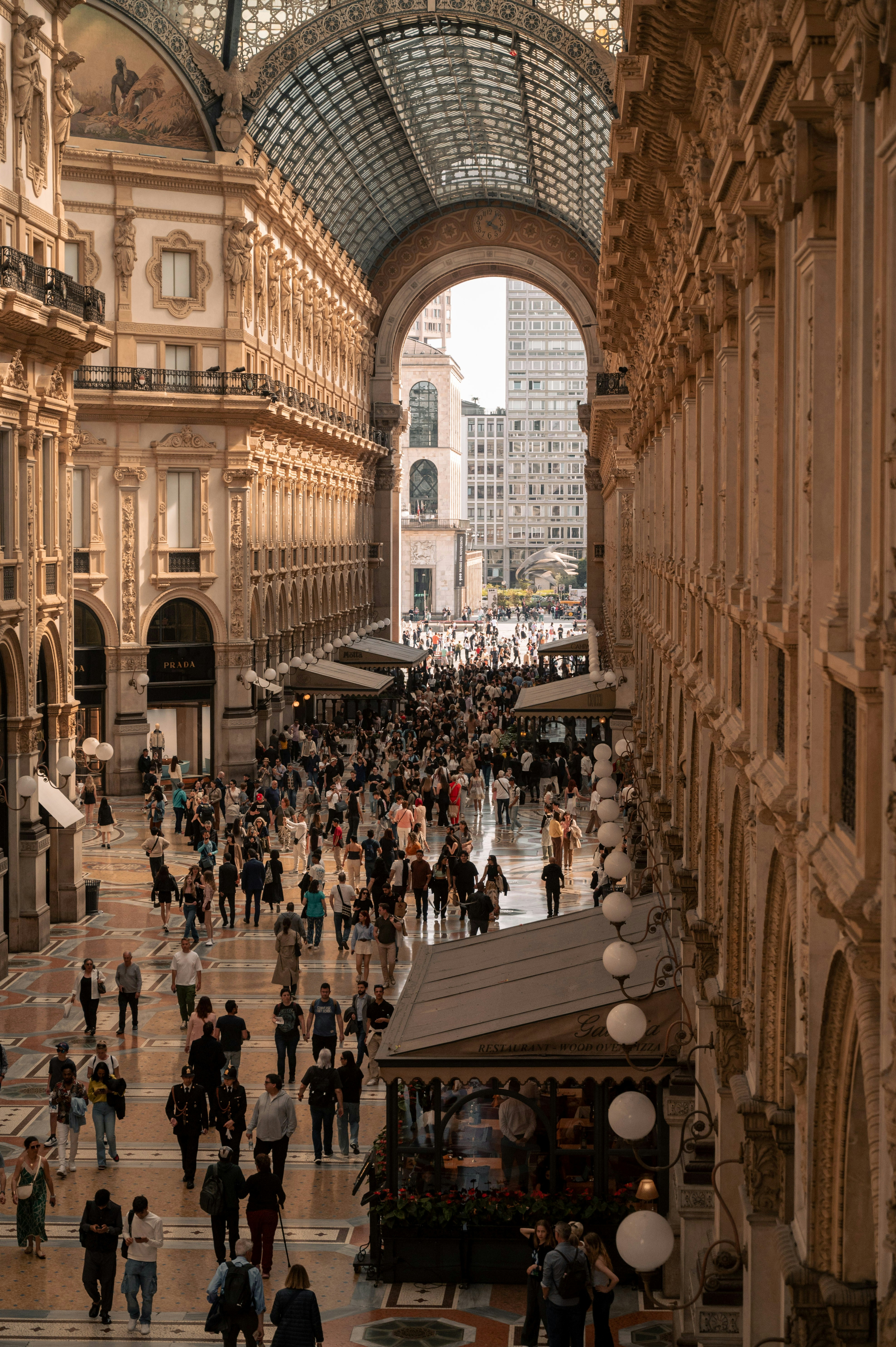 Crowd under a grand arcade: light pours through the ornate archway