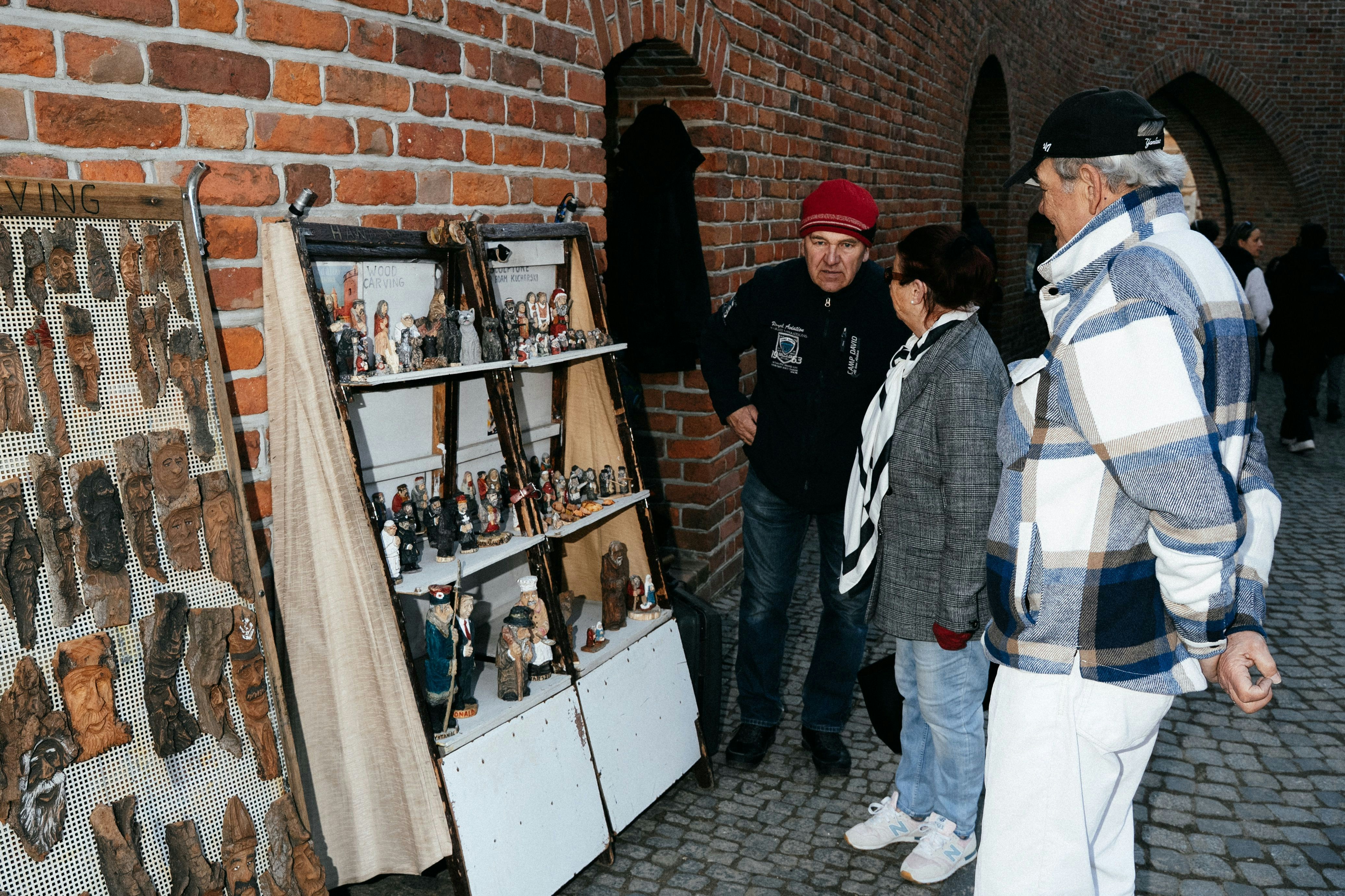 Market stall of carved figurines under an old brick arch