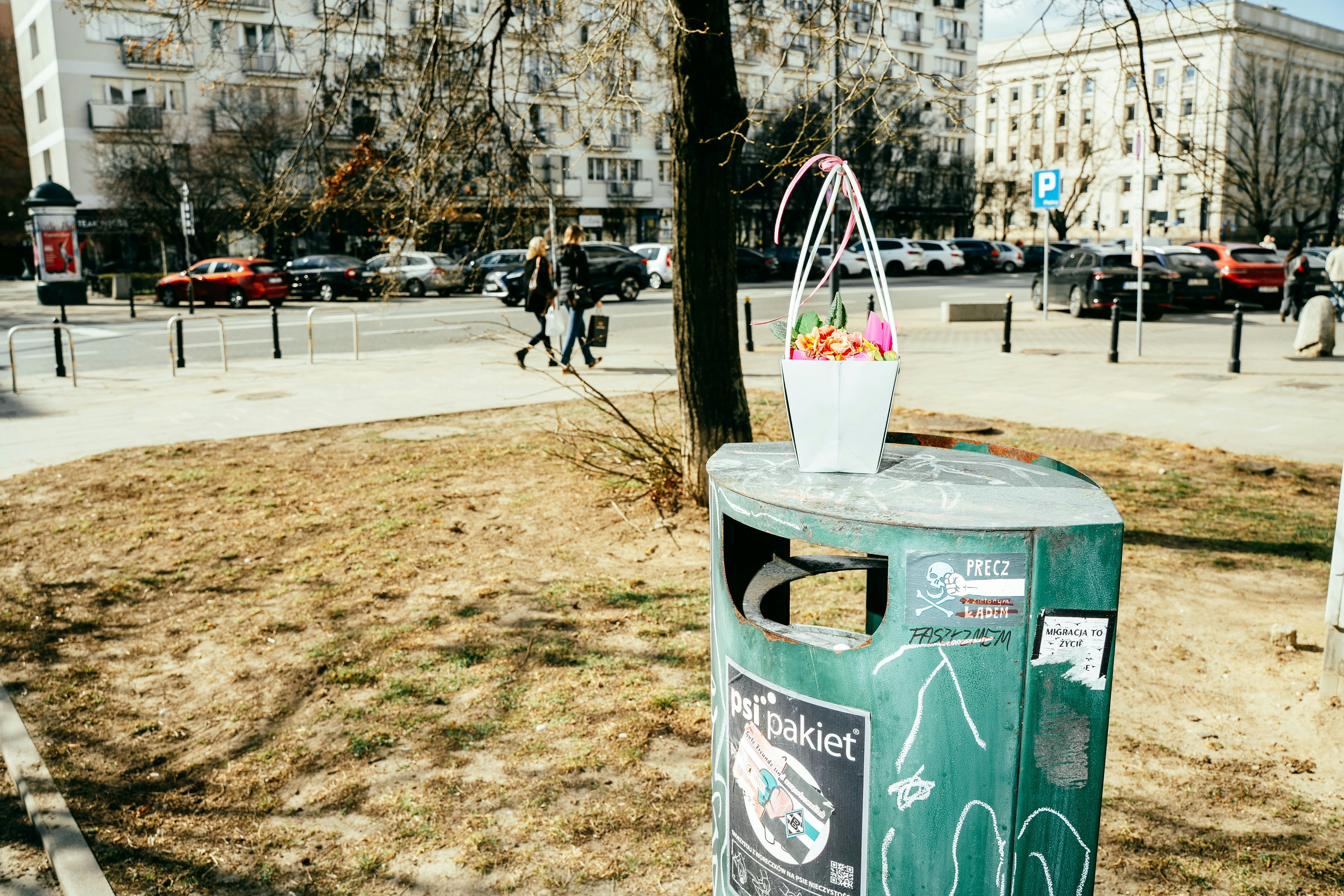 Flower Basket on a City Mood: A Kiss of Color Above the Green Bin