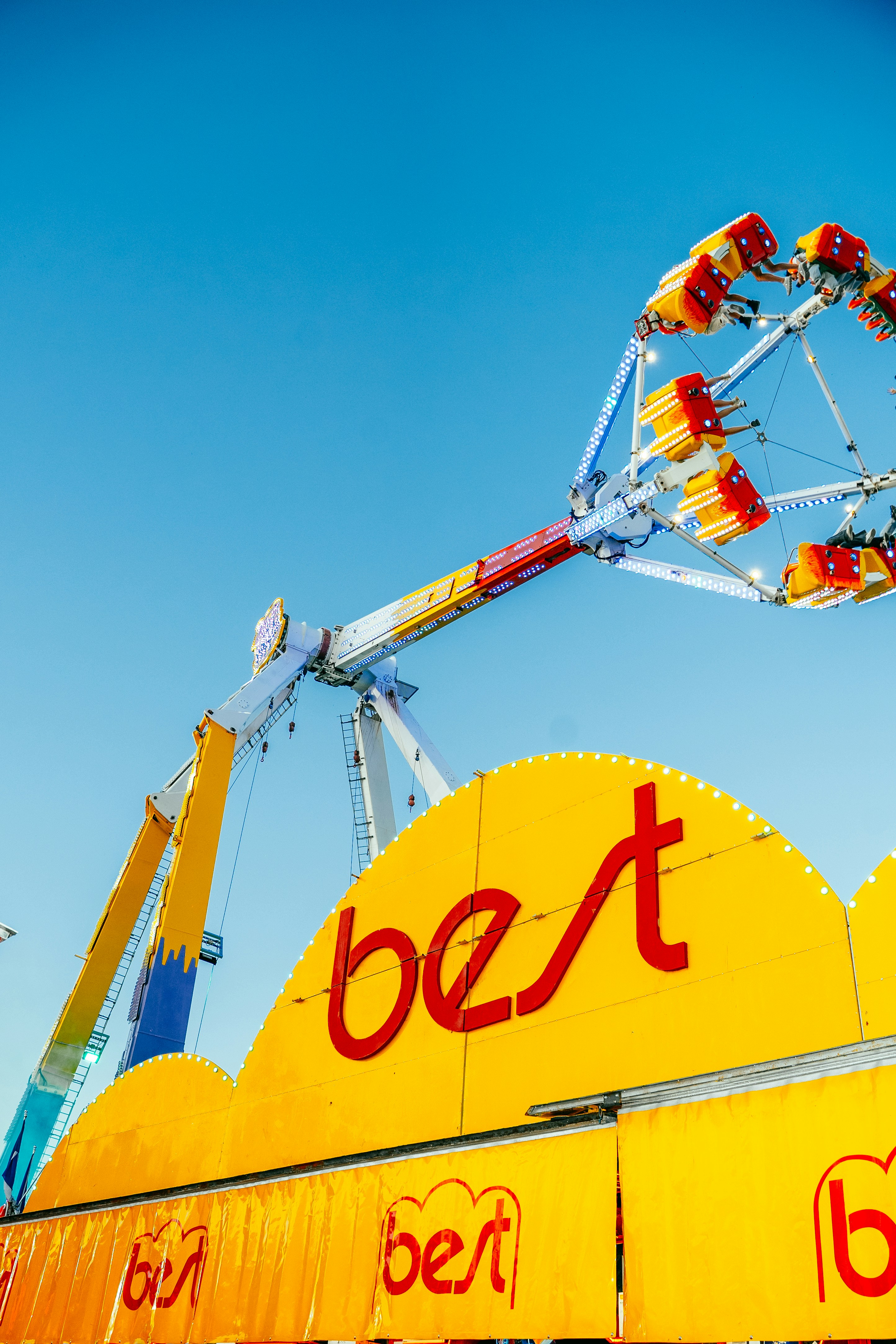 Sunlit Carnivale Wheels: A Bold Sign Basks in Blue Sky